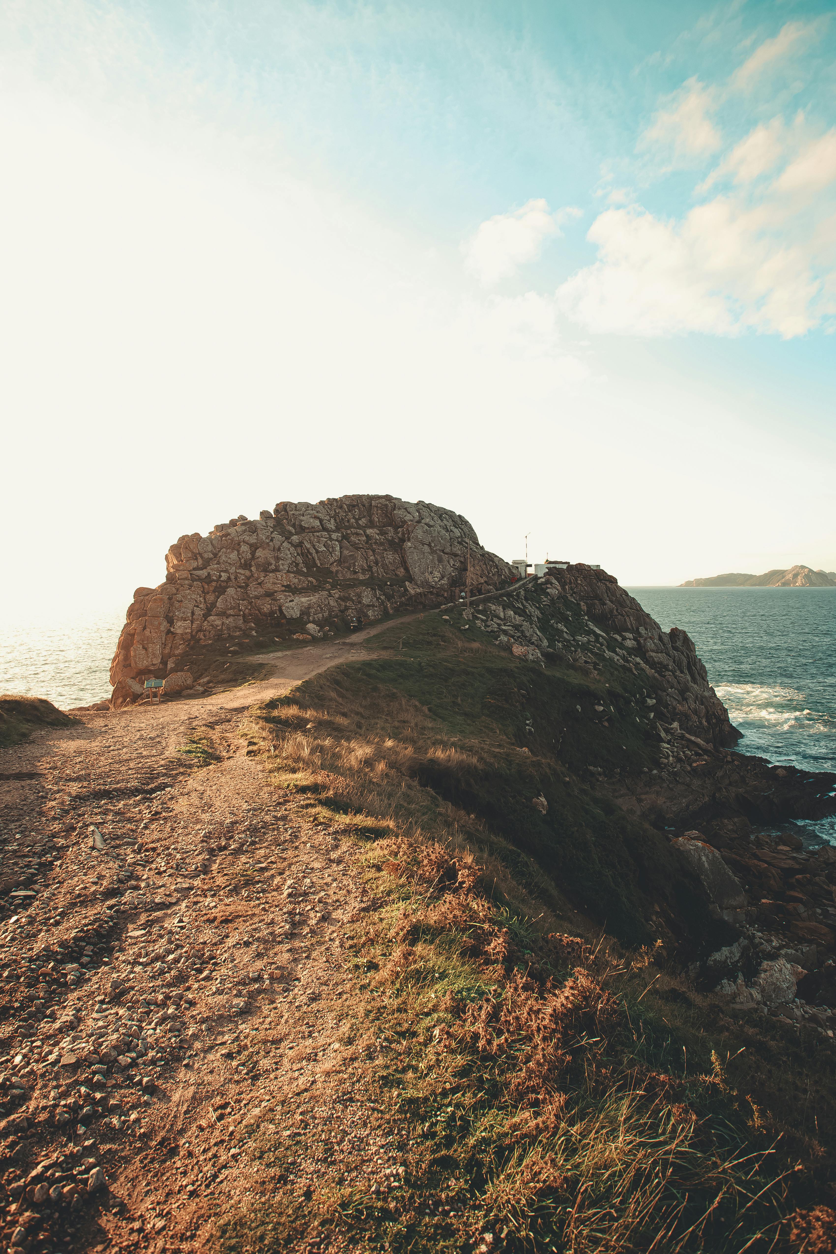 Rocky formations near ocean under cloudy sky · Free Stock Photo