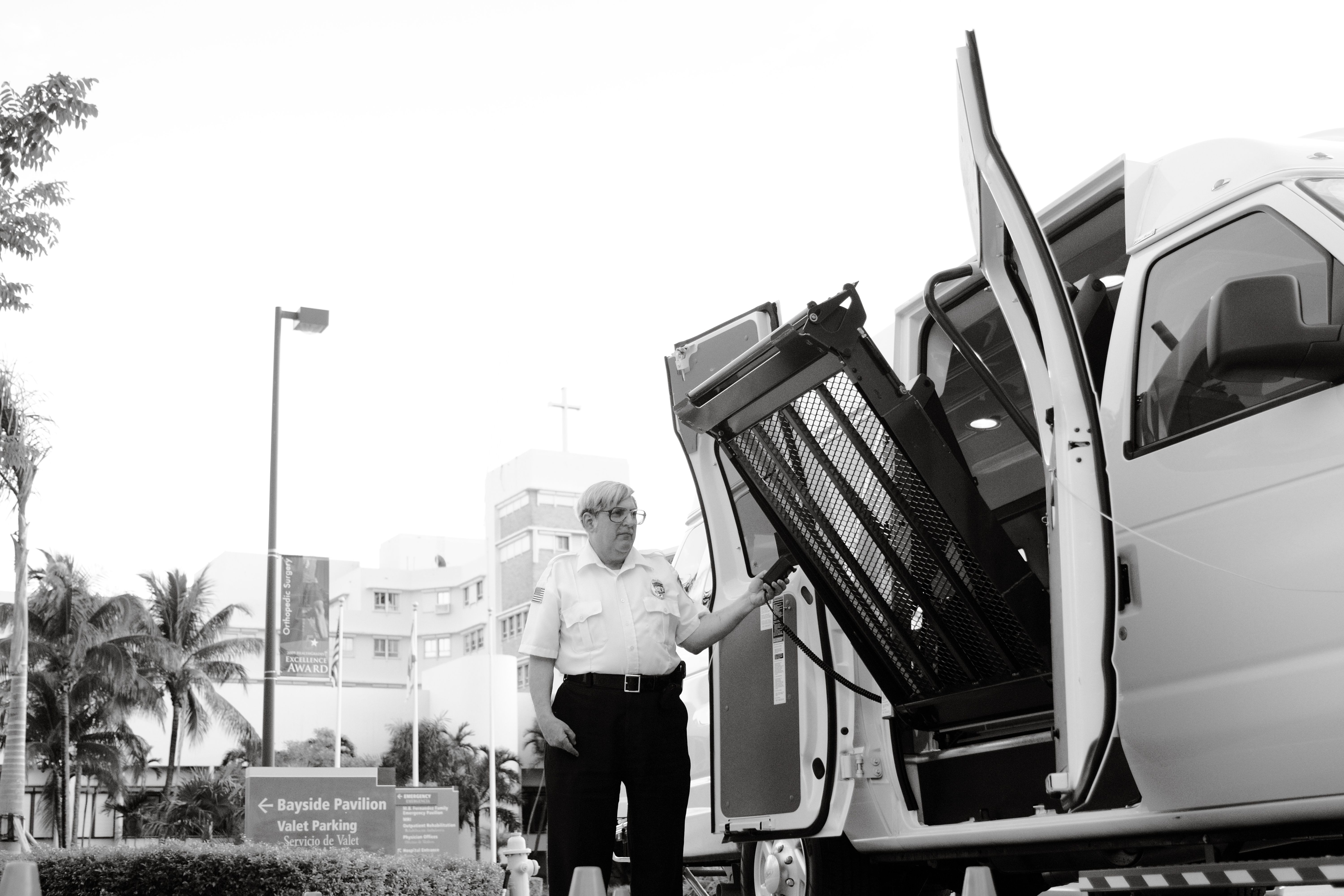 Security Guard Operating Vehicle Lift in Urban Setting · Free Stock Photo