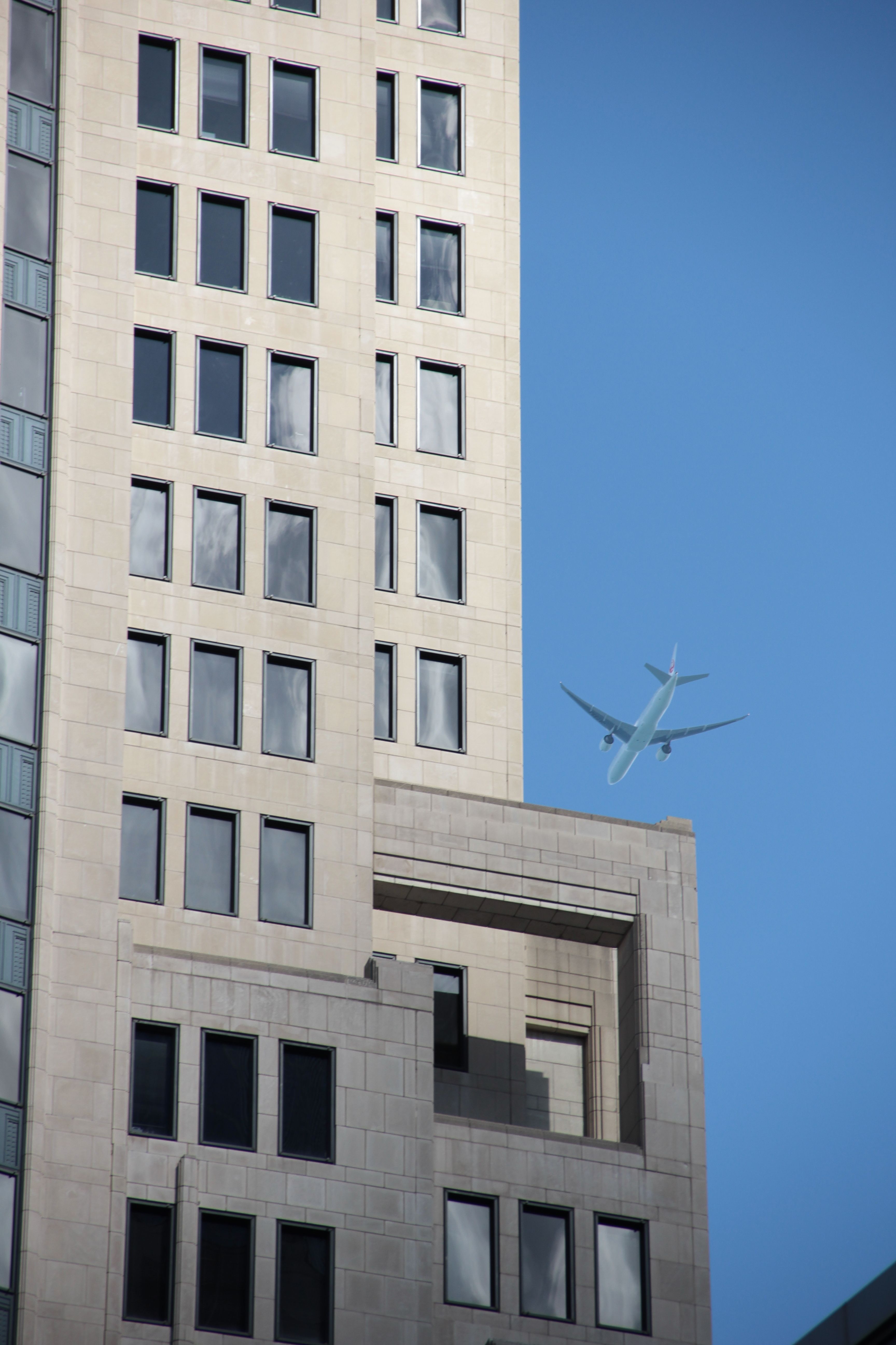 Airplane Flying Near Modern Architectural Building · Free Stock Photo