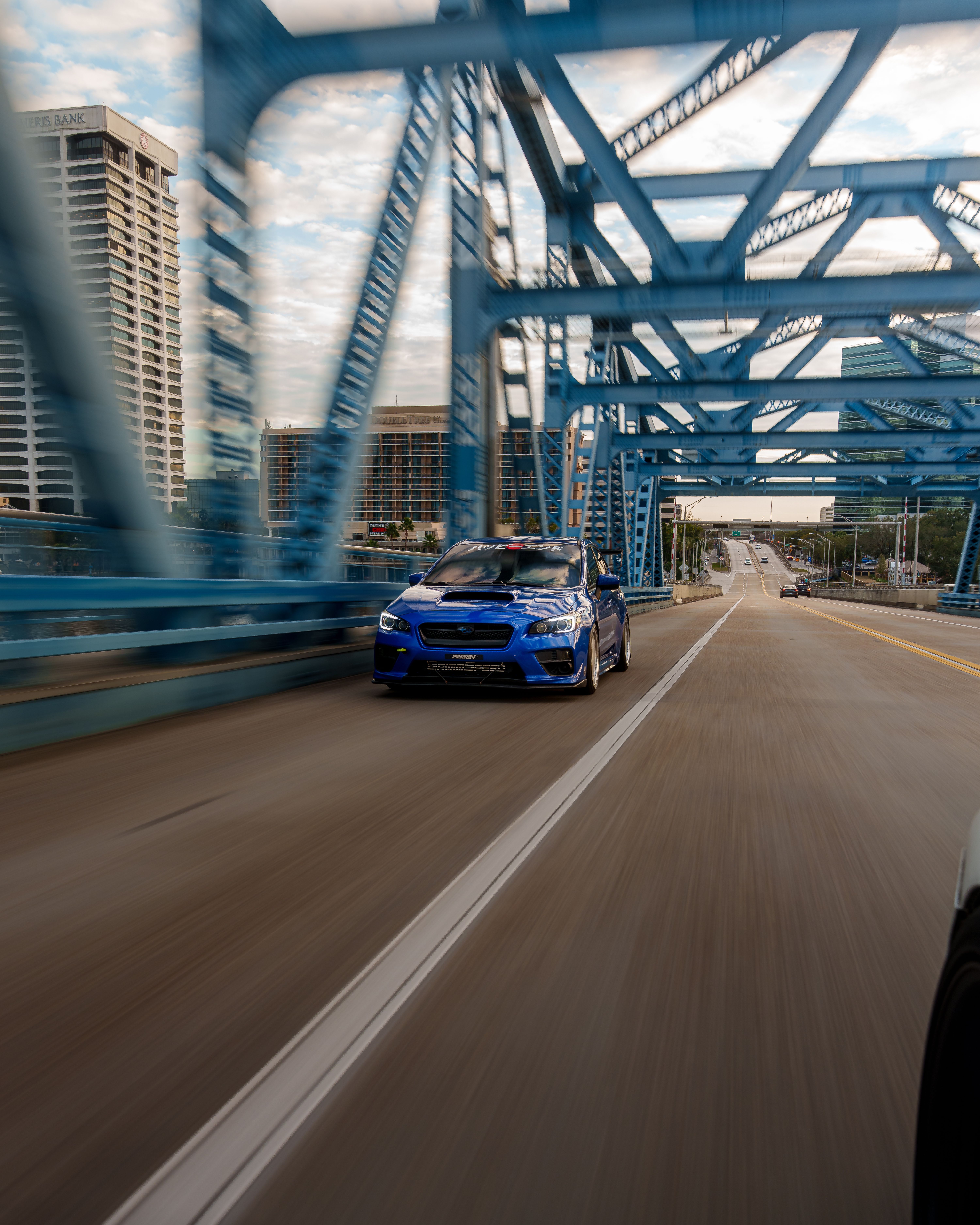 Blue Sports Car Crossing Iconic Steel Bridge · Free Stock Photo