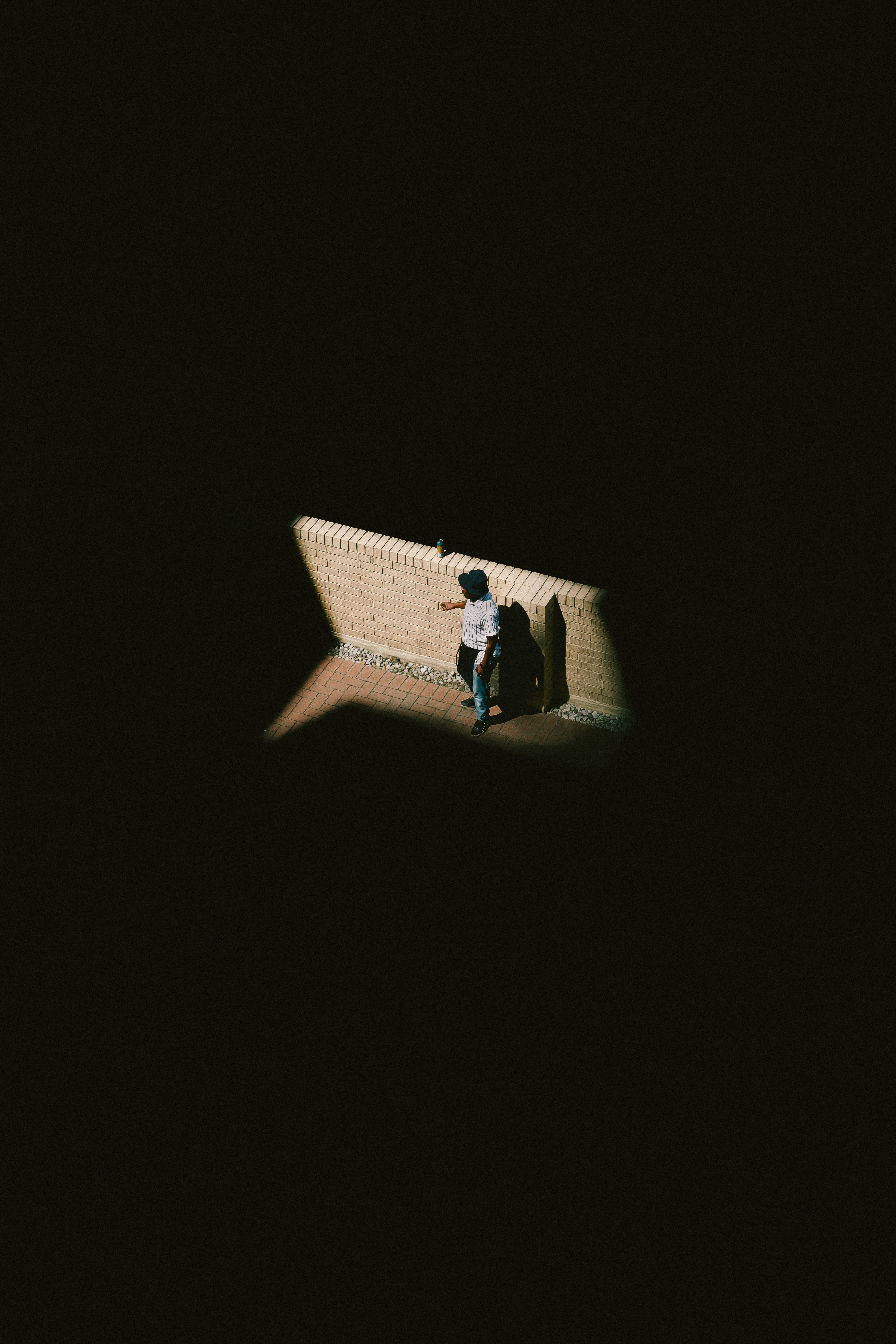 Person Leaning on Brick Wall in Shadowy Scene · Free Stock Photo