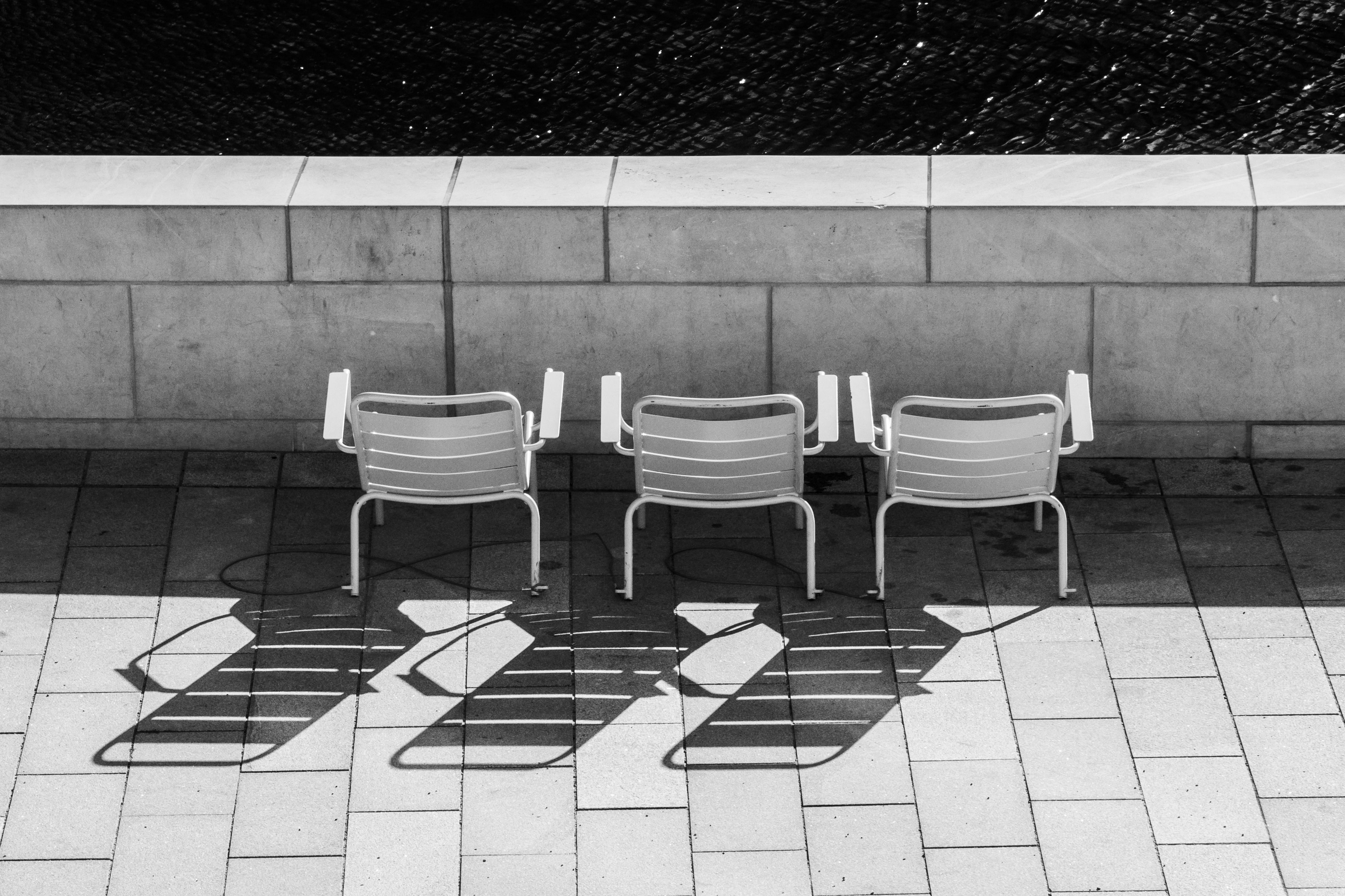 Three Empty Chairs Casting Shadows on Pavement · Free Stock Photo