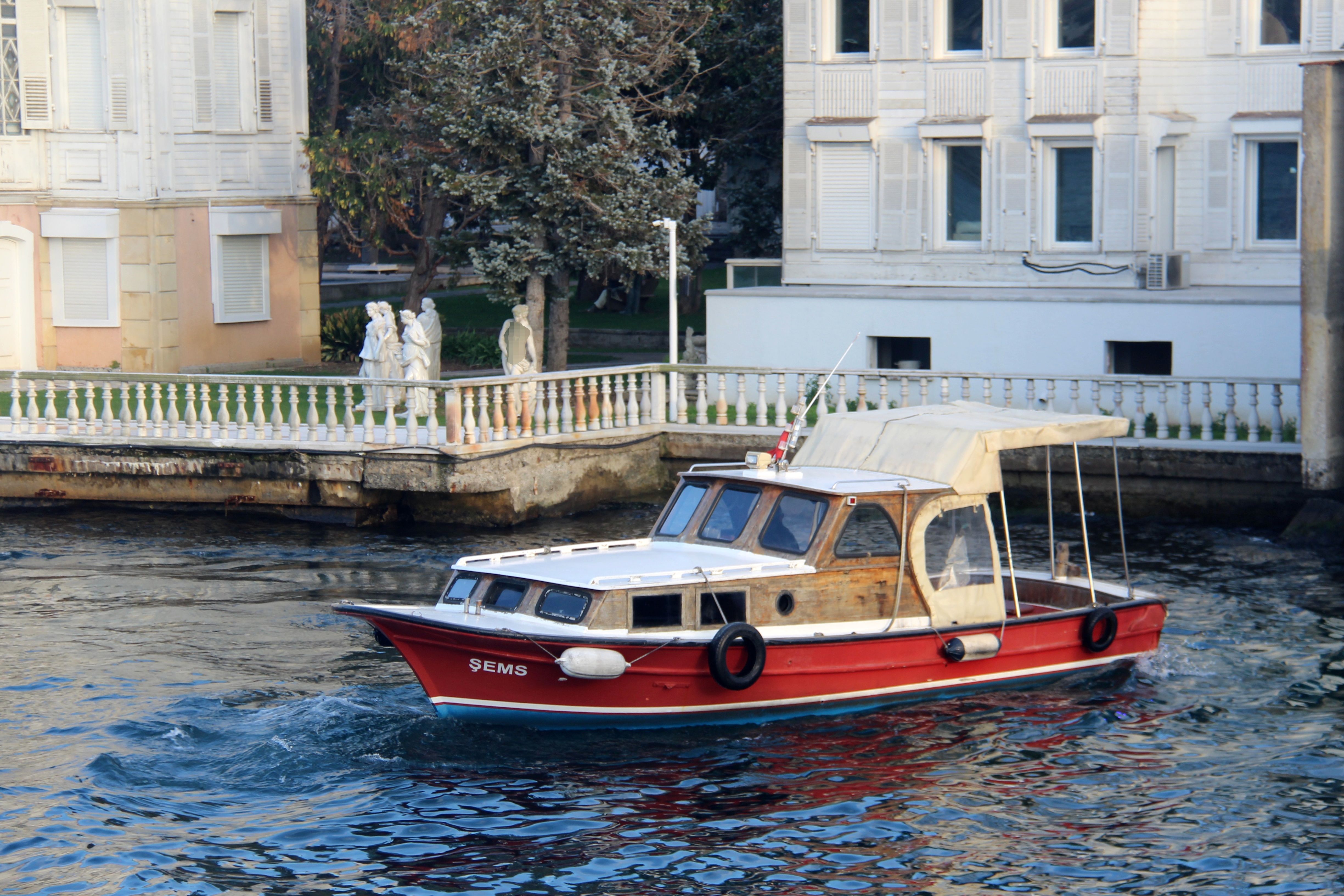 Red Boat Cruising by Historical Building · Free Stock Photo