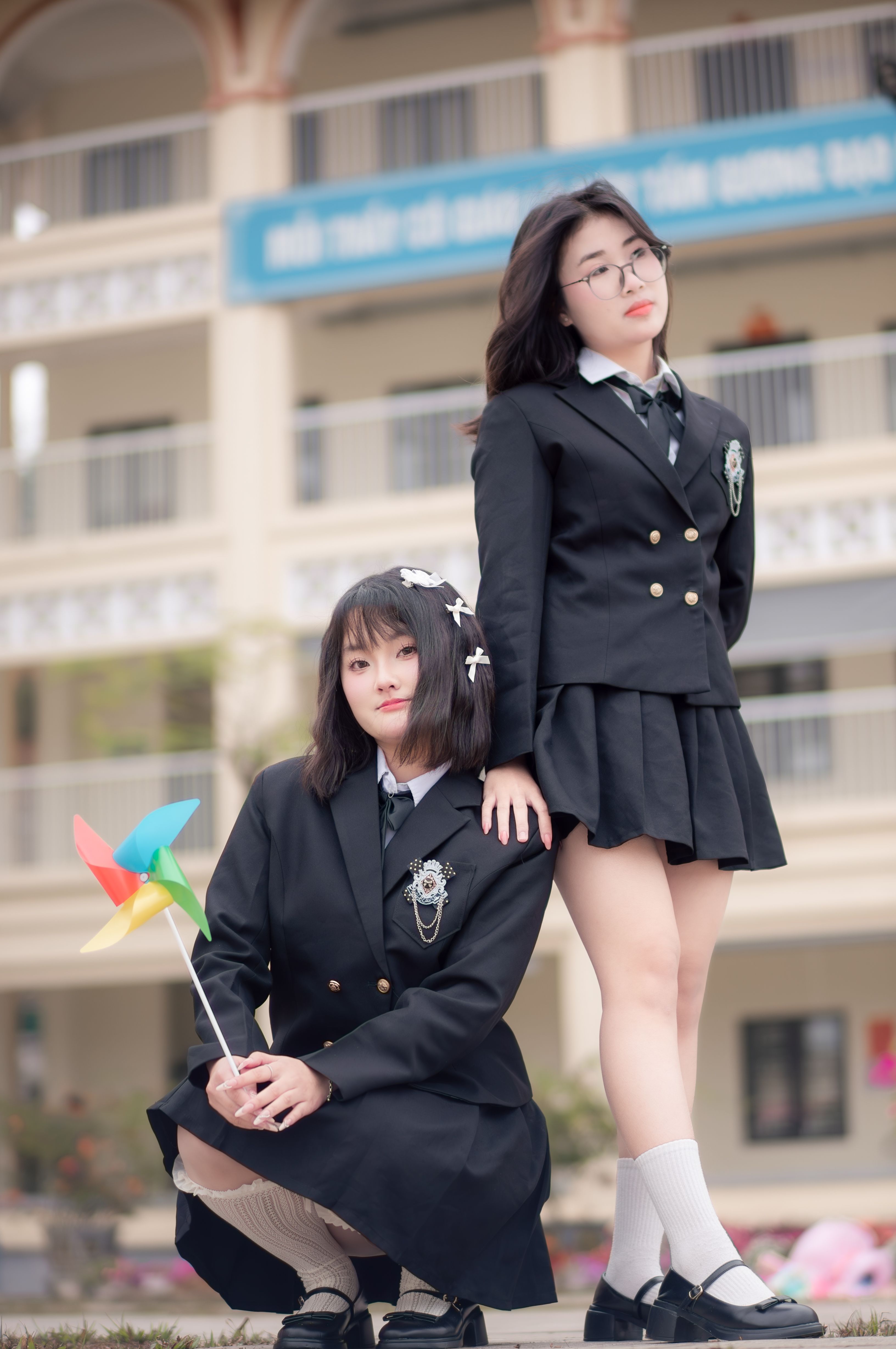 Two Girls in Uniforms with Pinwheel Outdoors · Free Stock Photo