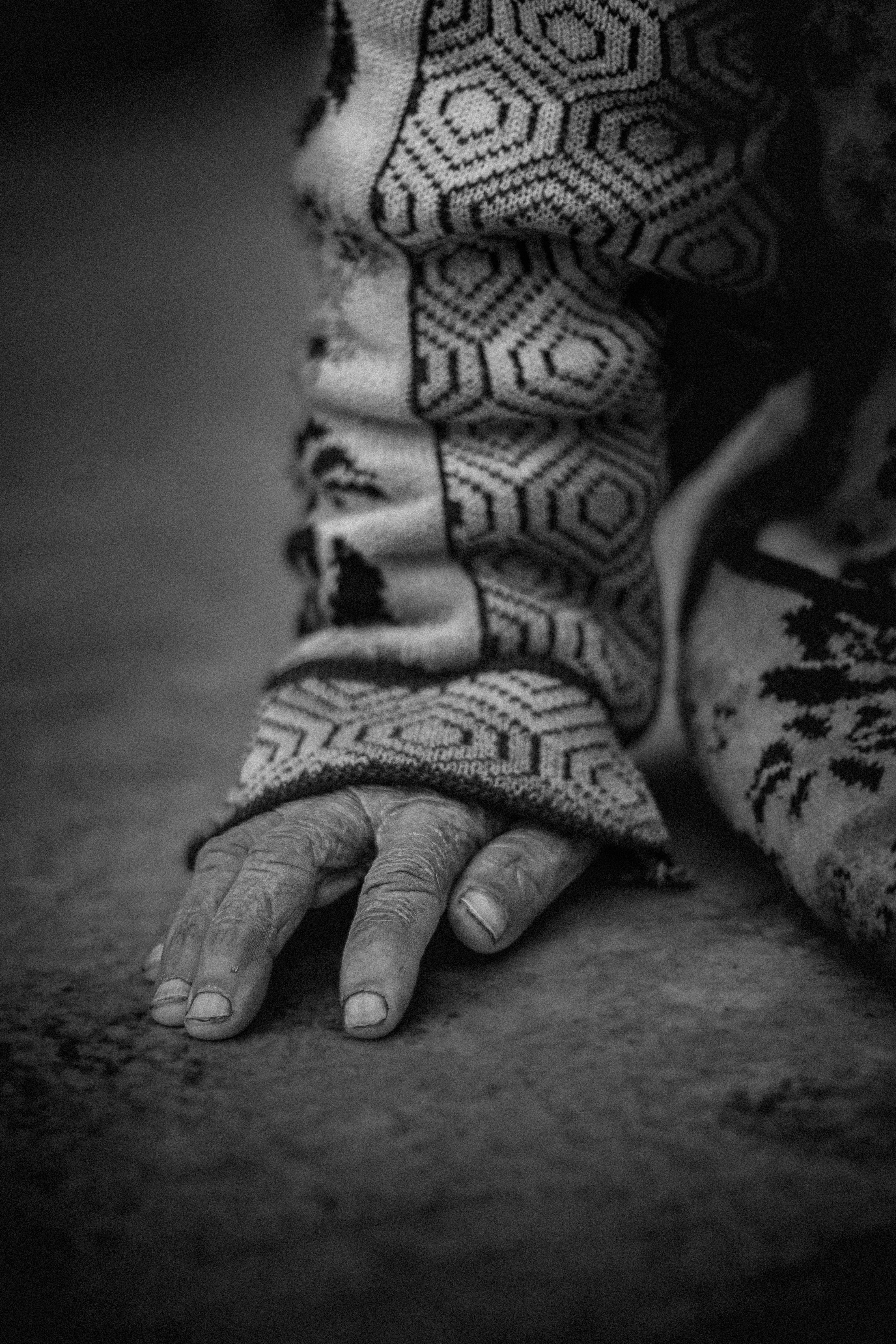 Elderly Hand Resting on Rough Ground in Black and White · Free Stock Photo