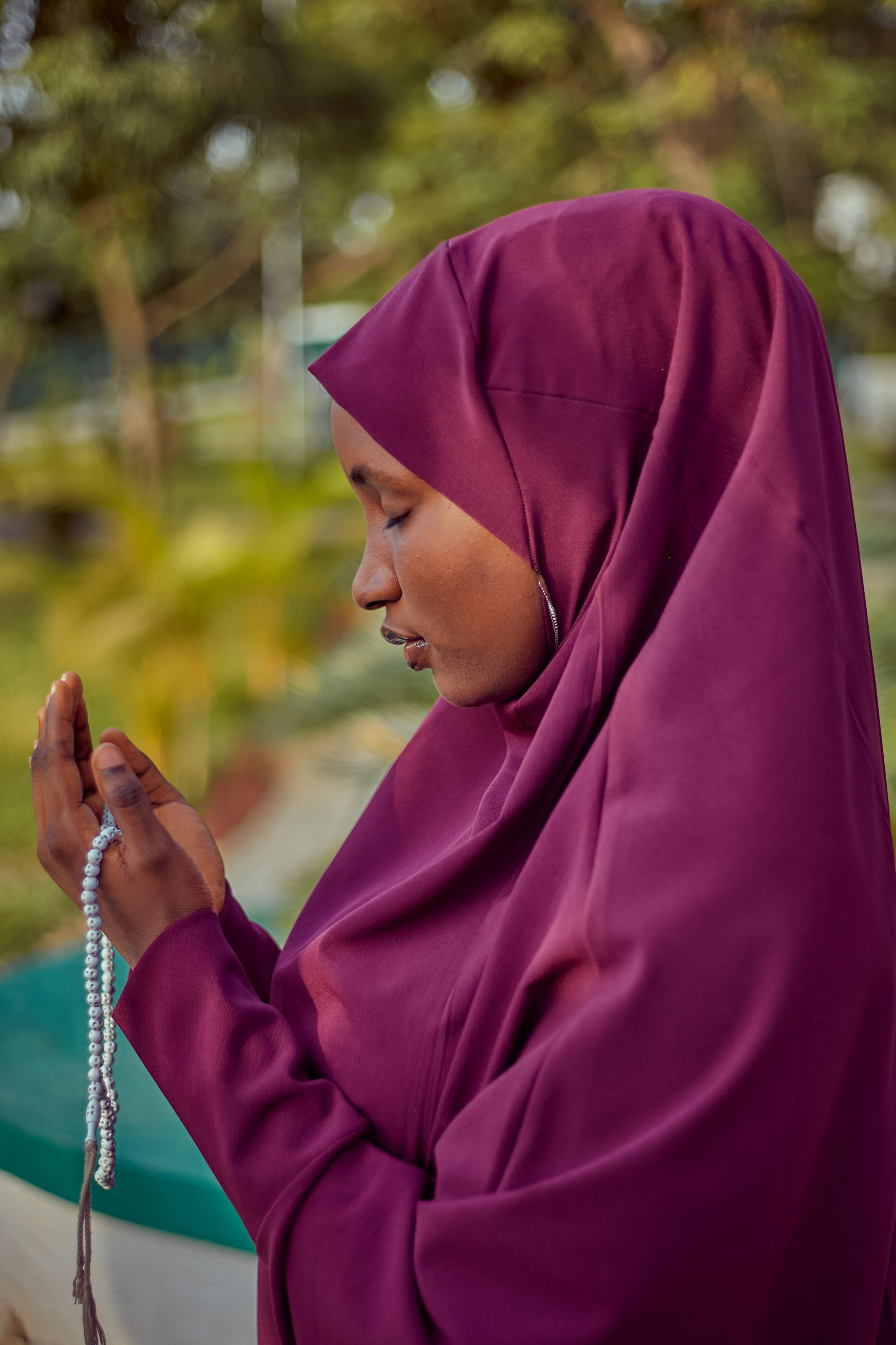 Woman in Hijab Praying Outdoors with Prayer Beads · Free Stock Photo