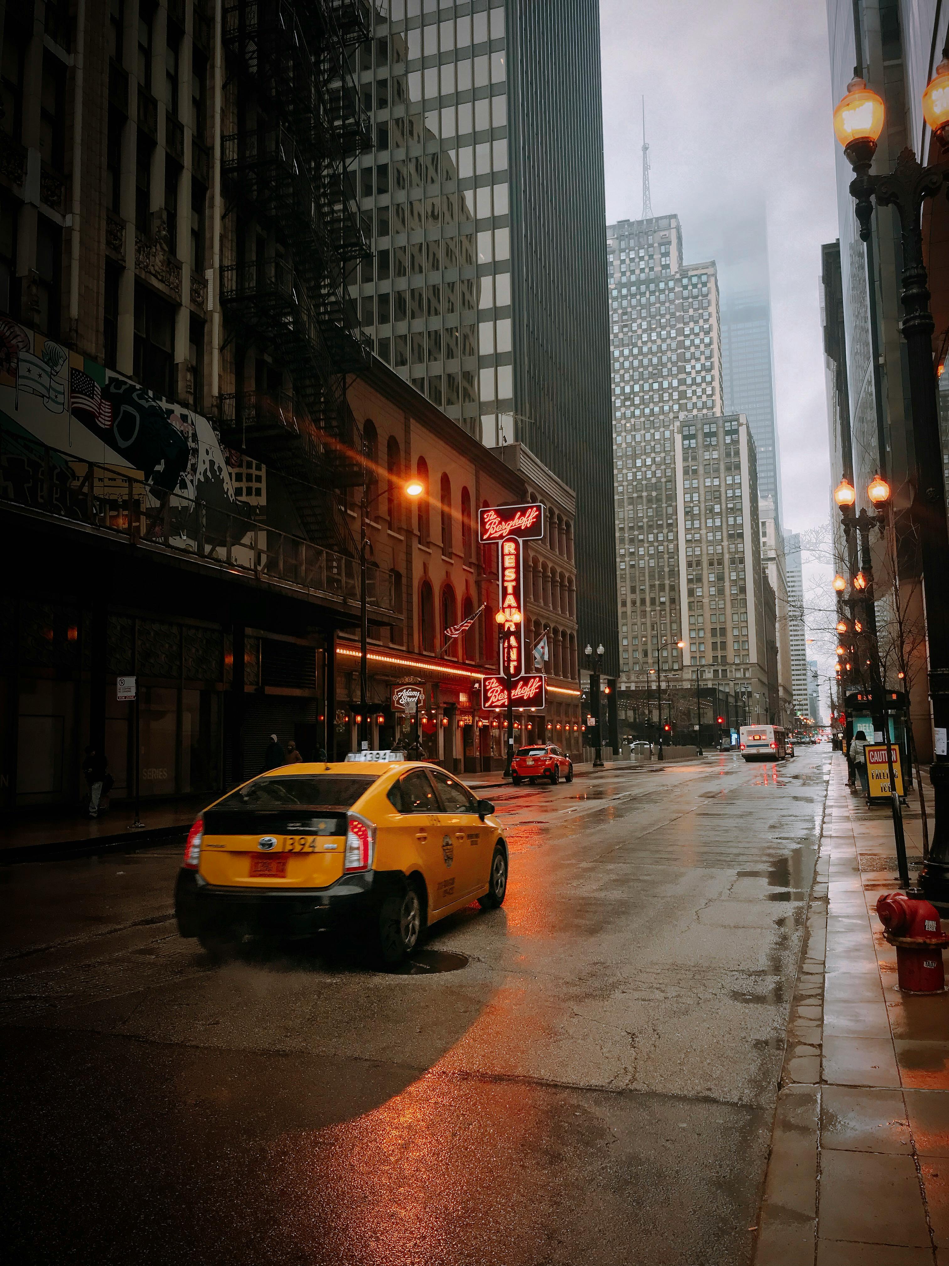Yellow Taxi On The Road In Between High Rise Buildings · Free Stock Photo