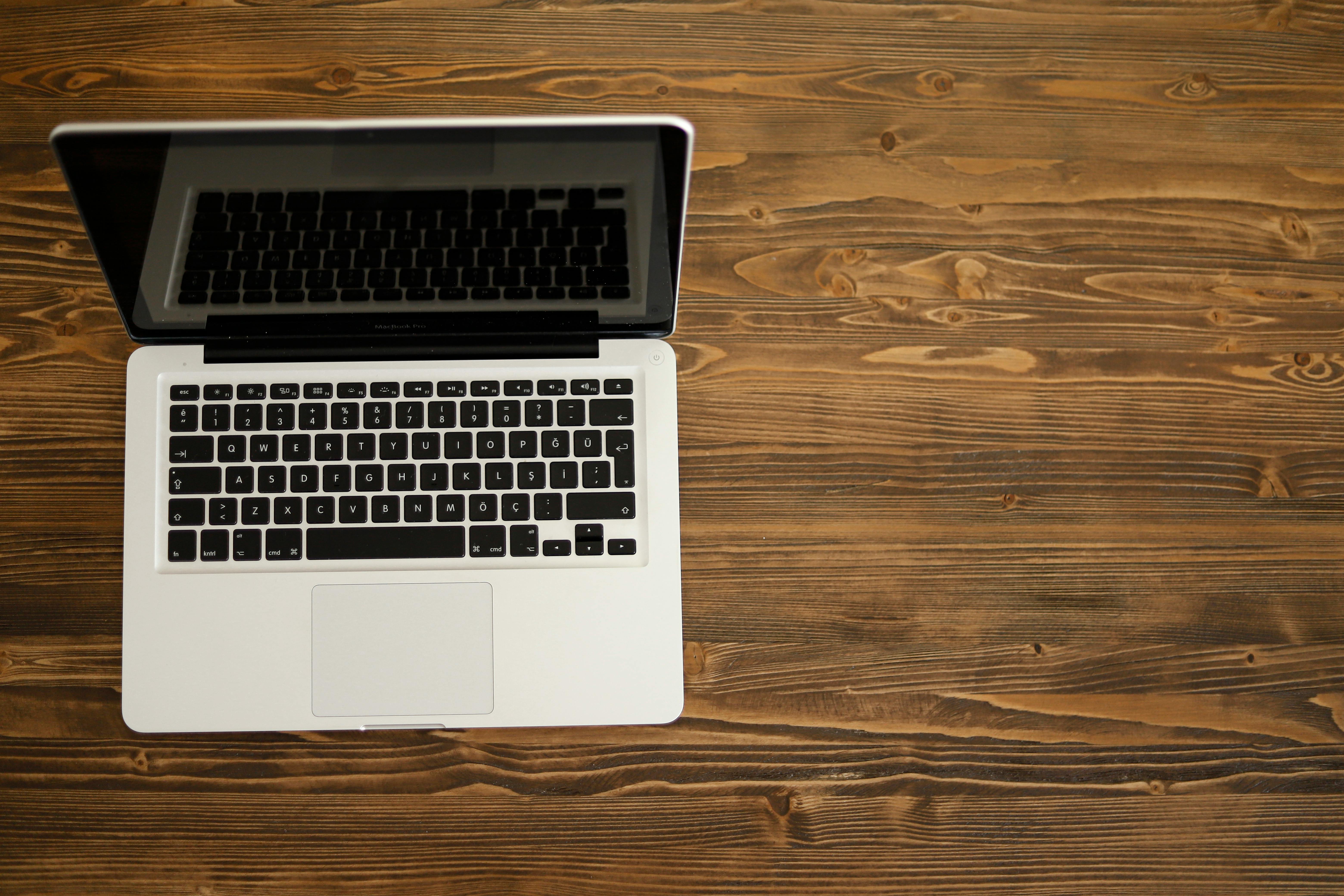 Macbook Pro On Brown Wooden Table · Free Stock Photo