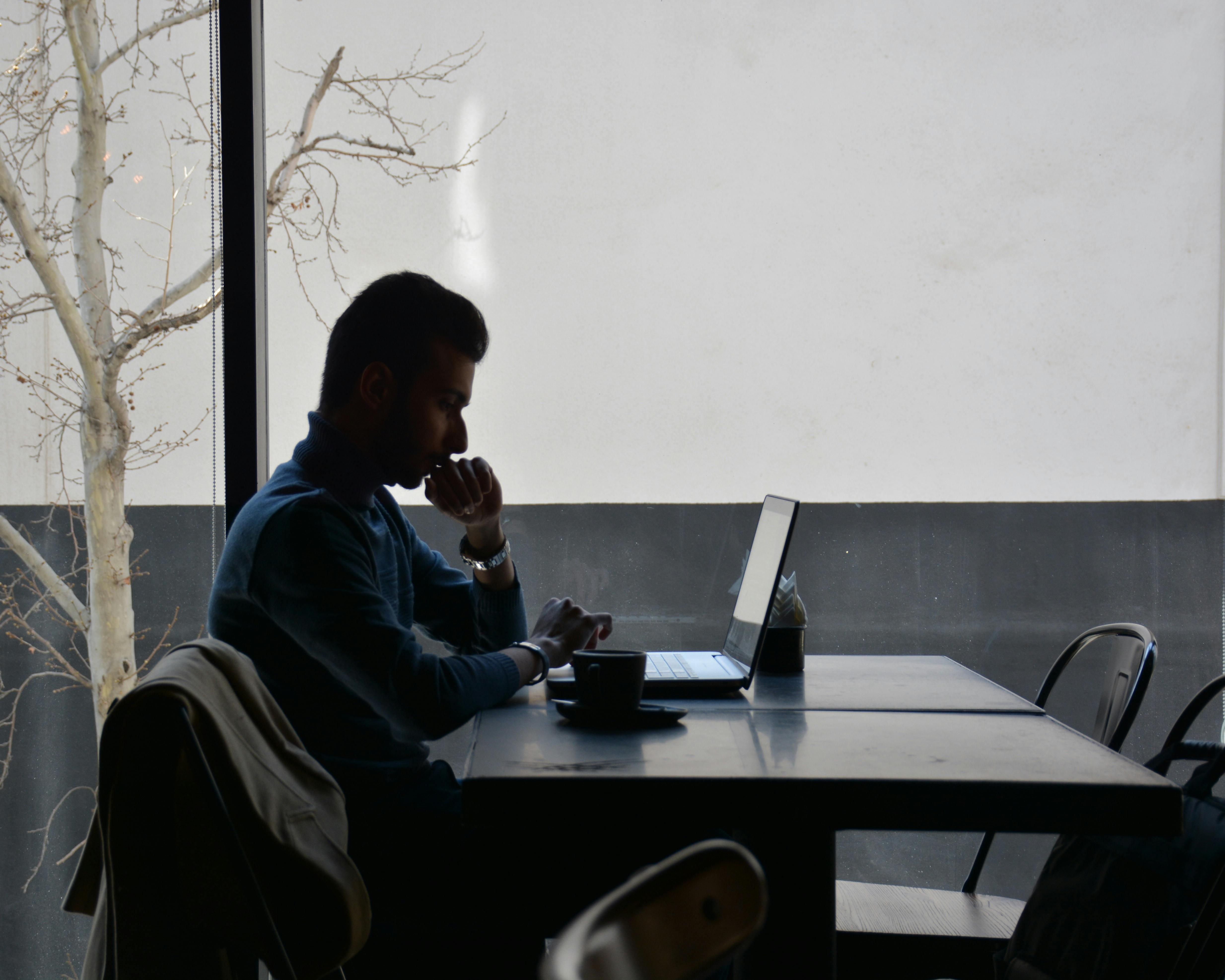 Man Sitting on Chair While Using a Laptop · Free Stock Photo