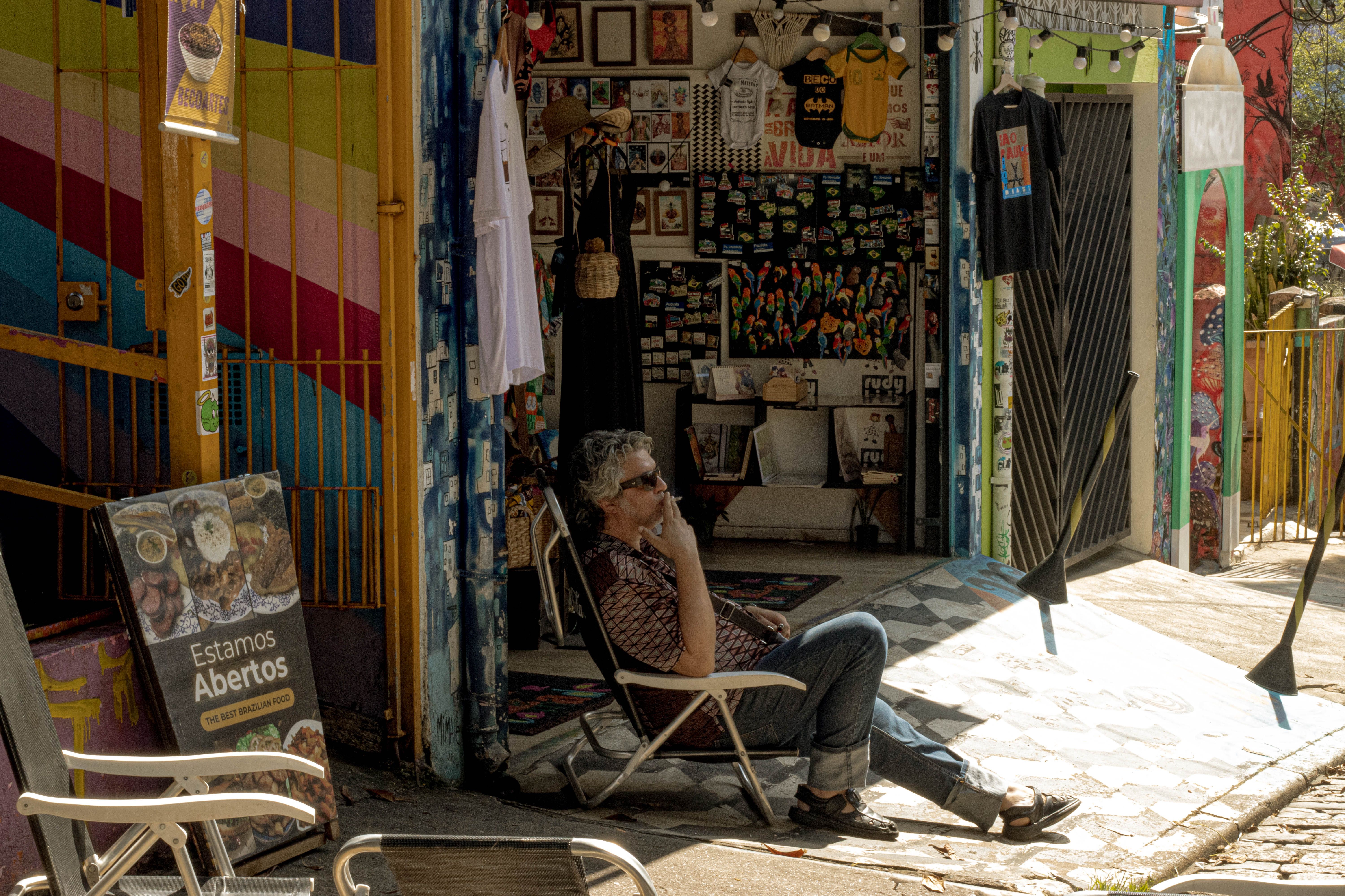 Relaxed Man Outside Colorful Artisan Shop · Free Stock Photo