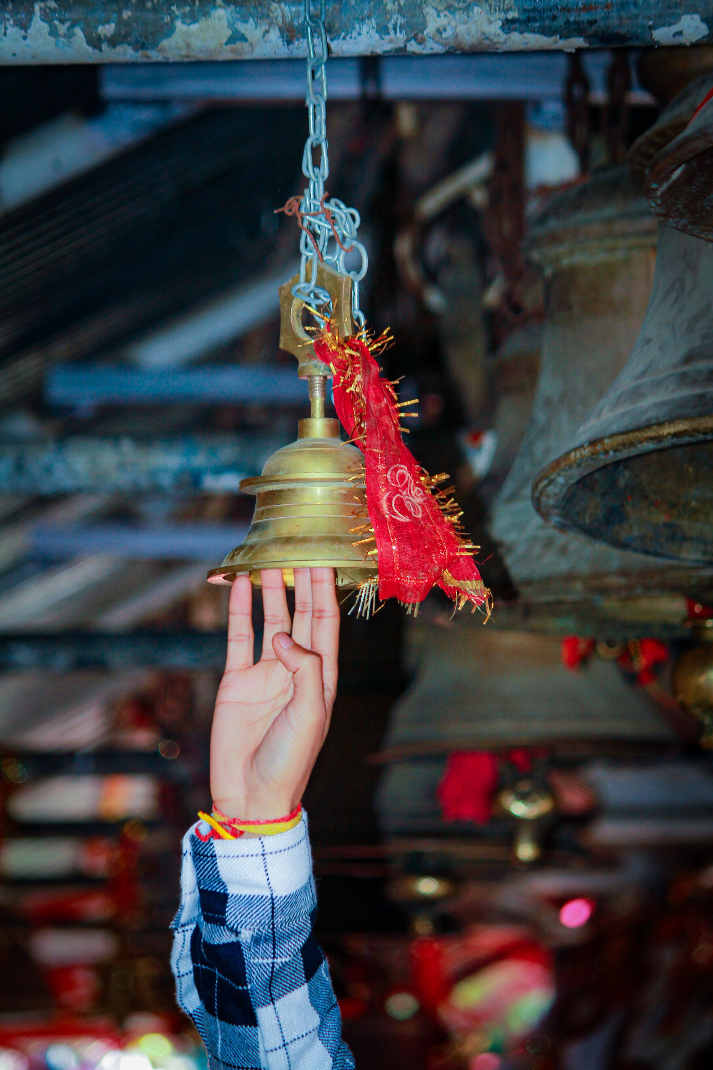 Hand reaching for a brass bell in a temple · Free Stock Photo