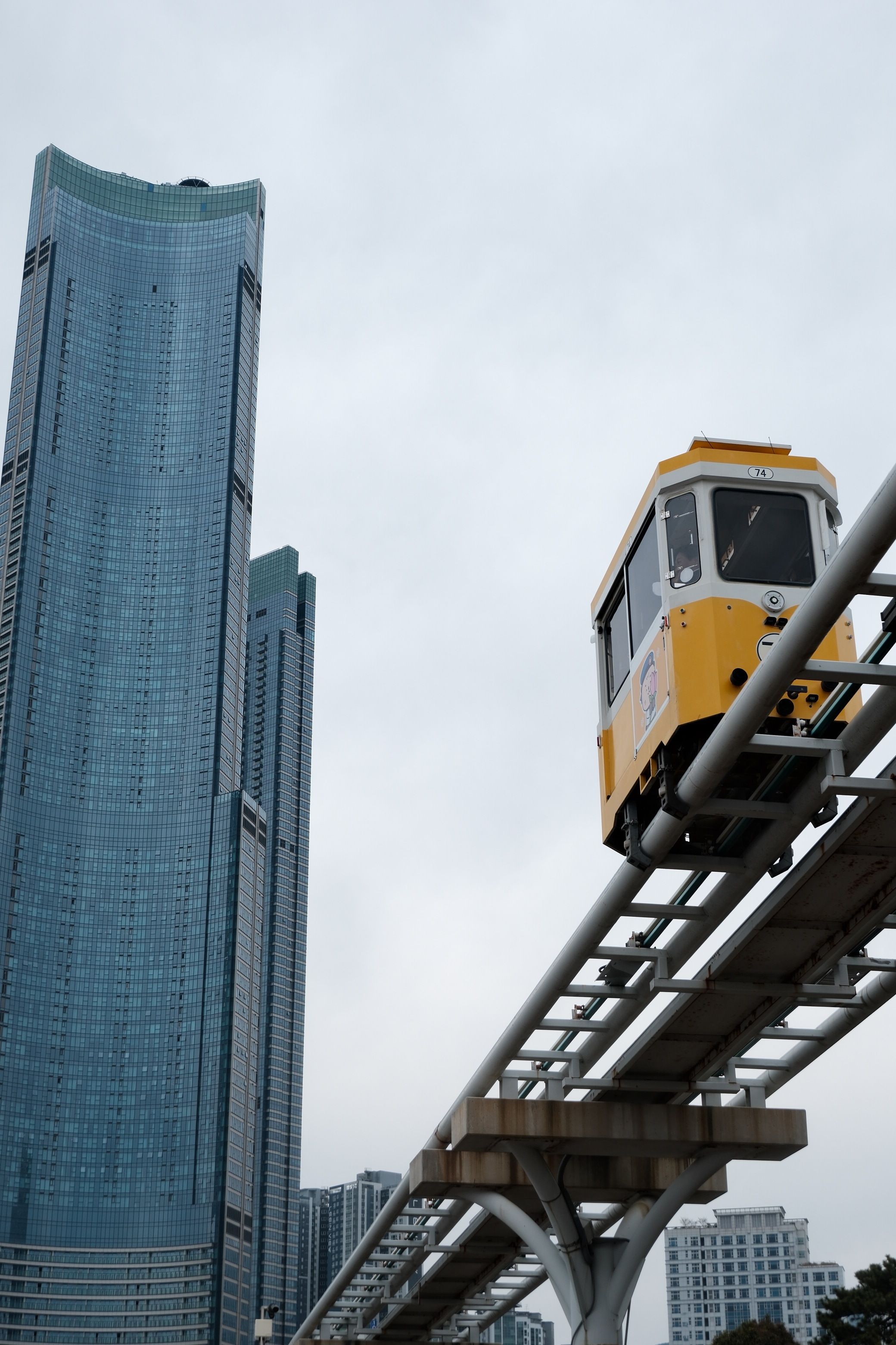 Monorail Passing Skyscraper in Overcast Cityscape · Free Stock Photo