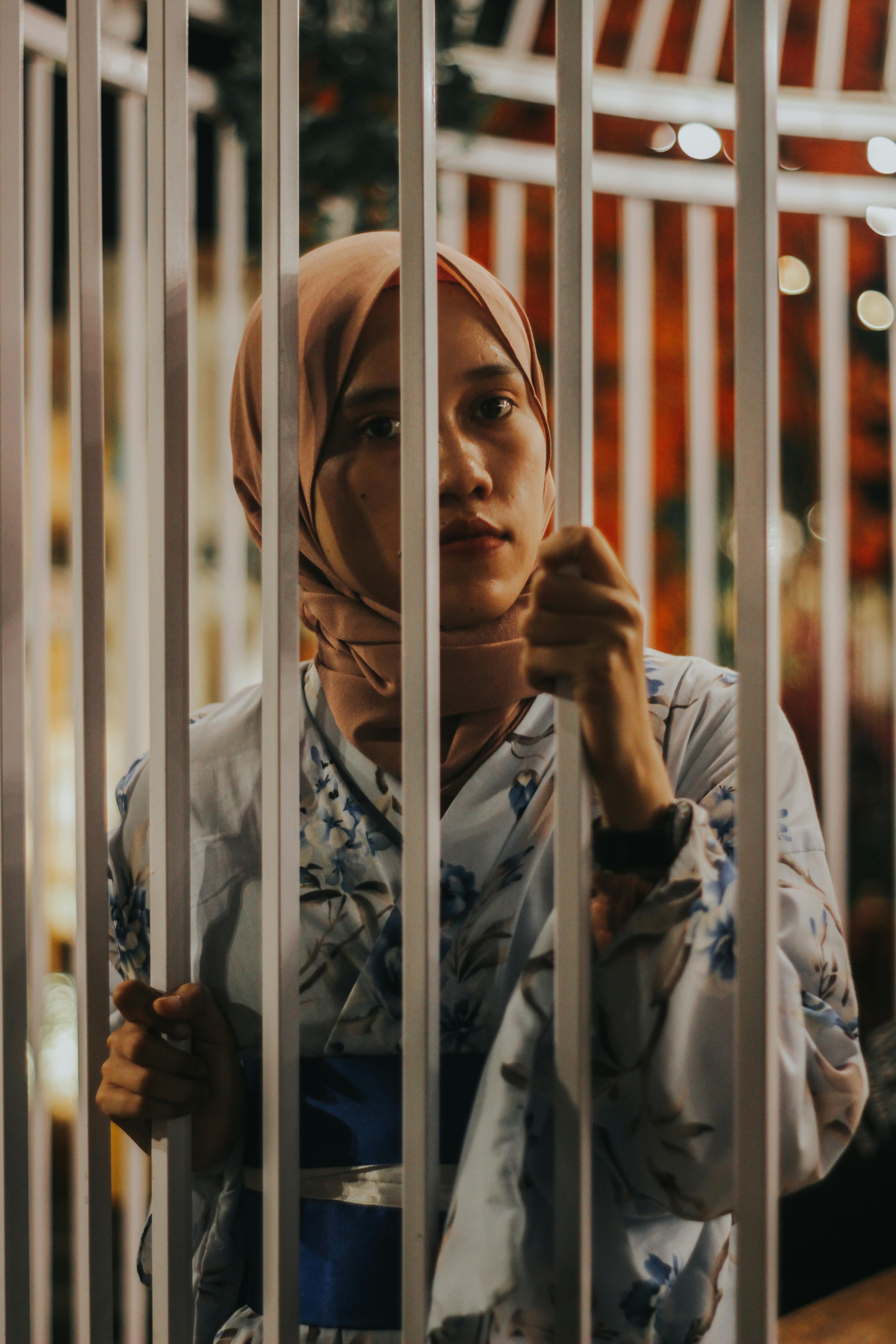 Woman in Brown Hijab Standing Behind Grey Metal Fence · Free Stock Photo