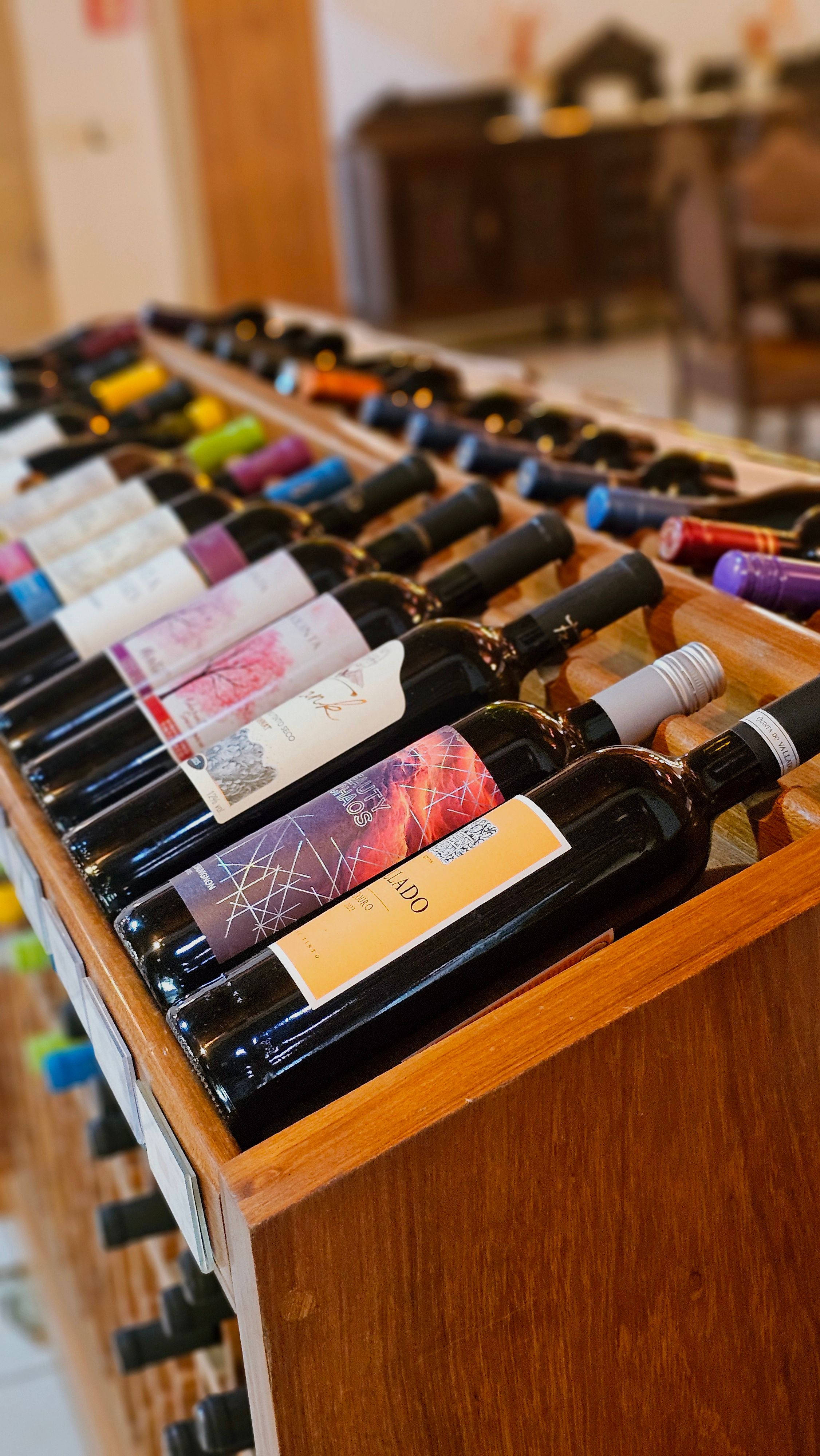 Colorful Wine Bottles Displayed on Wooden Rack · Free Stock Photo