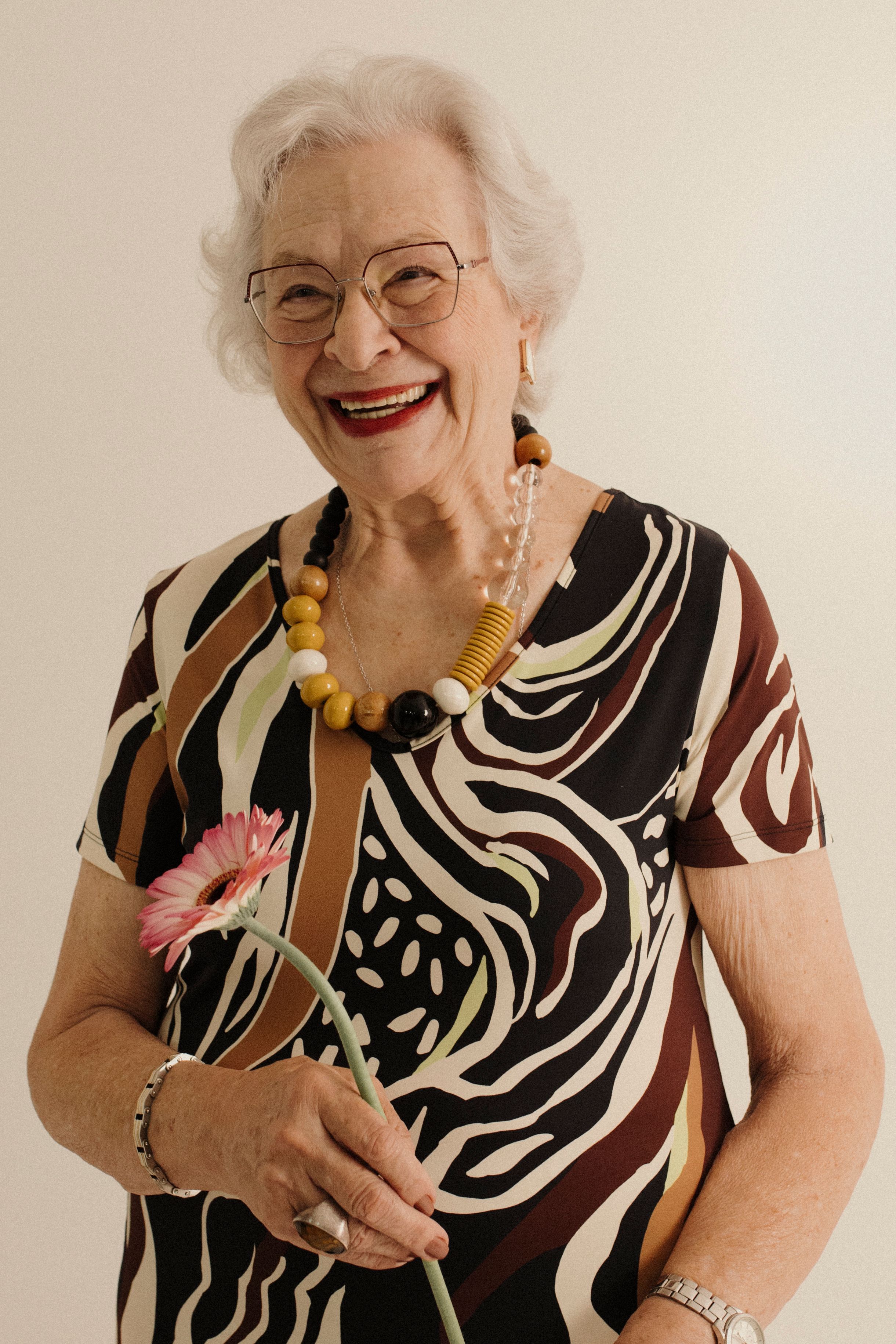 Anciana Sonriendo Con Una Gerbera Rosa. · Foto de stock gratuita