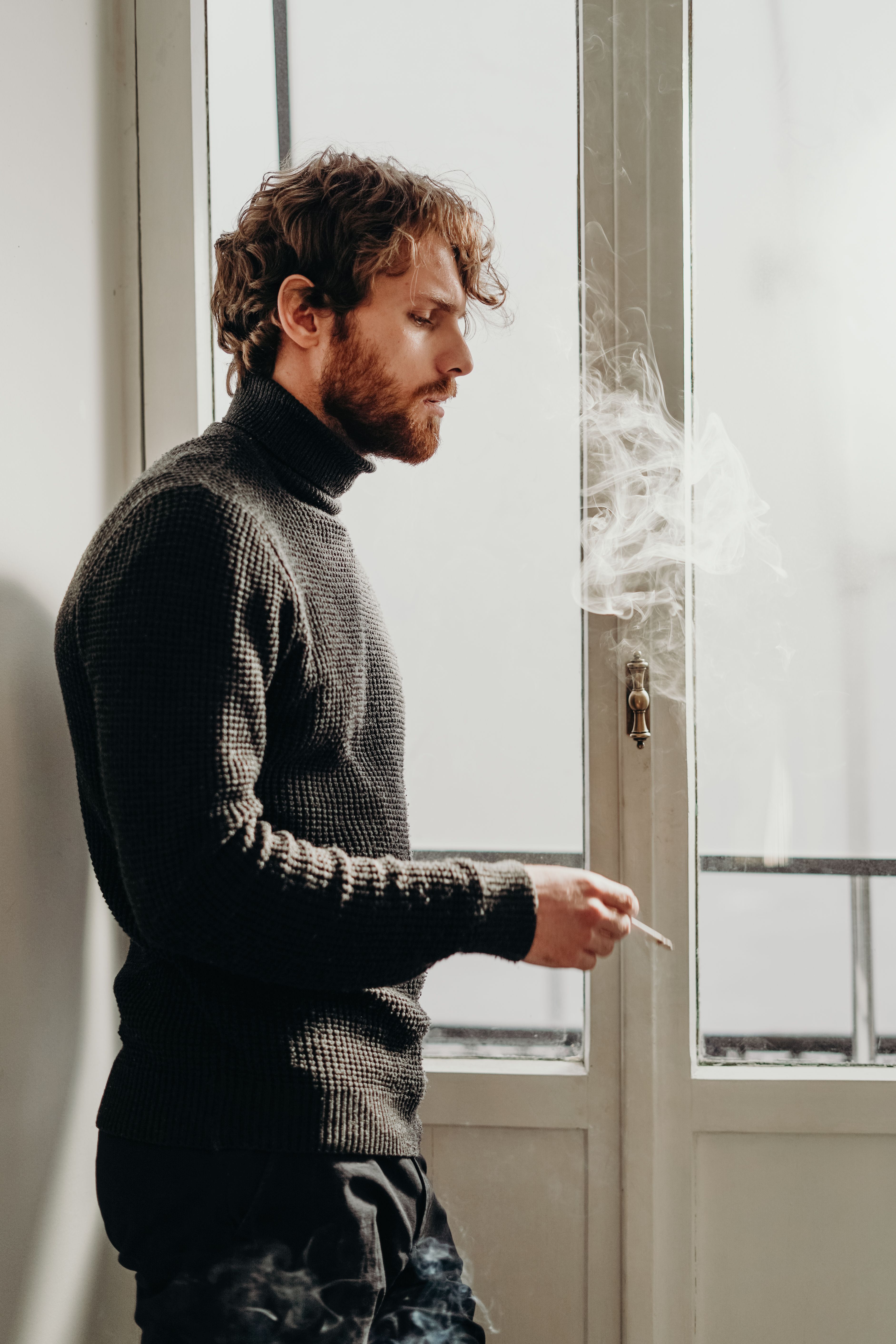 Side View Photo of Man in Black Sweater Standing Beside White Wooden ...