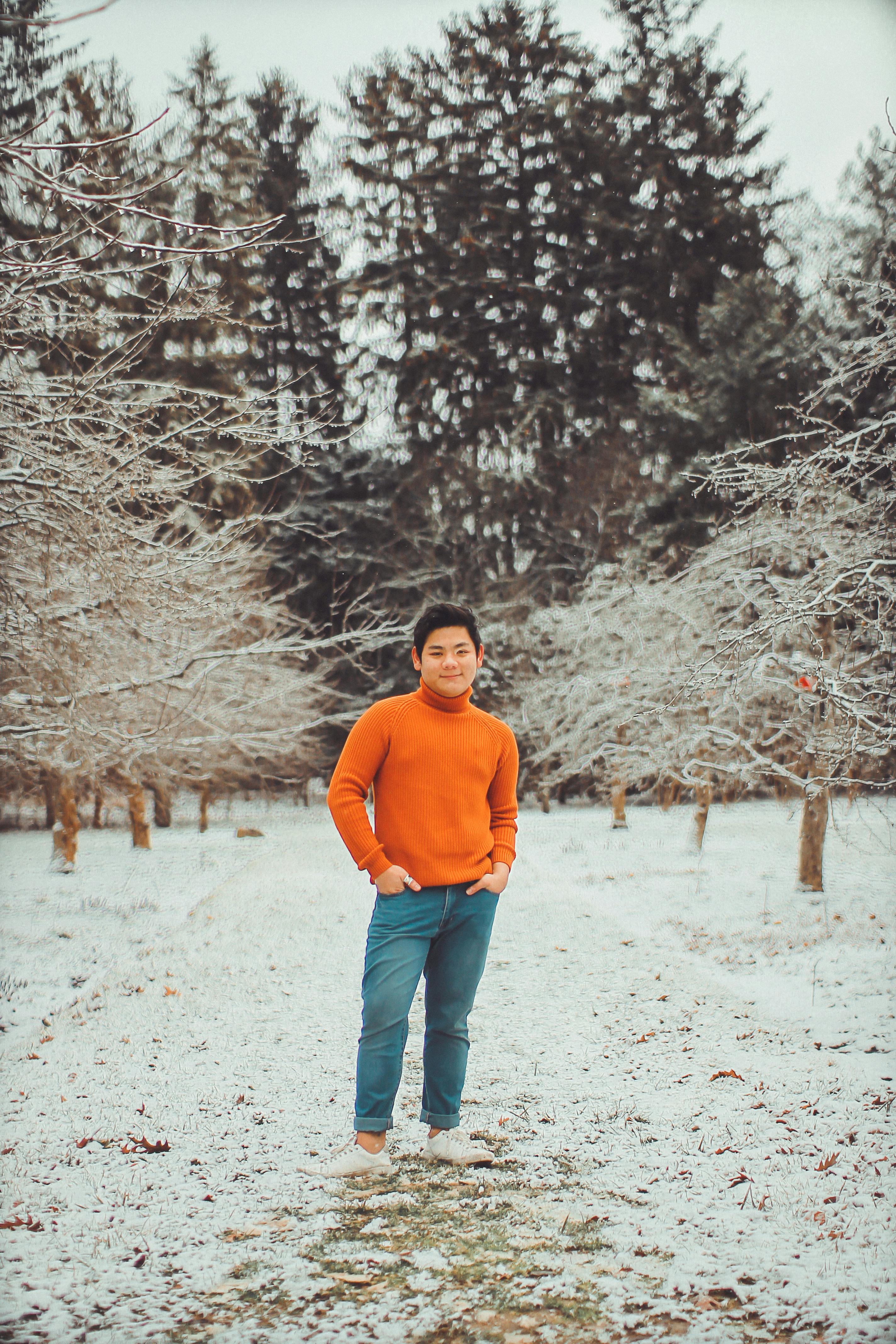 Man in Orange Sweater And Blue Denim Pants Standing Behind Tree Branch ...