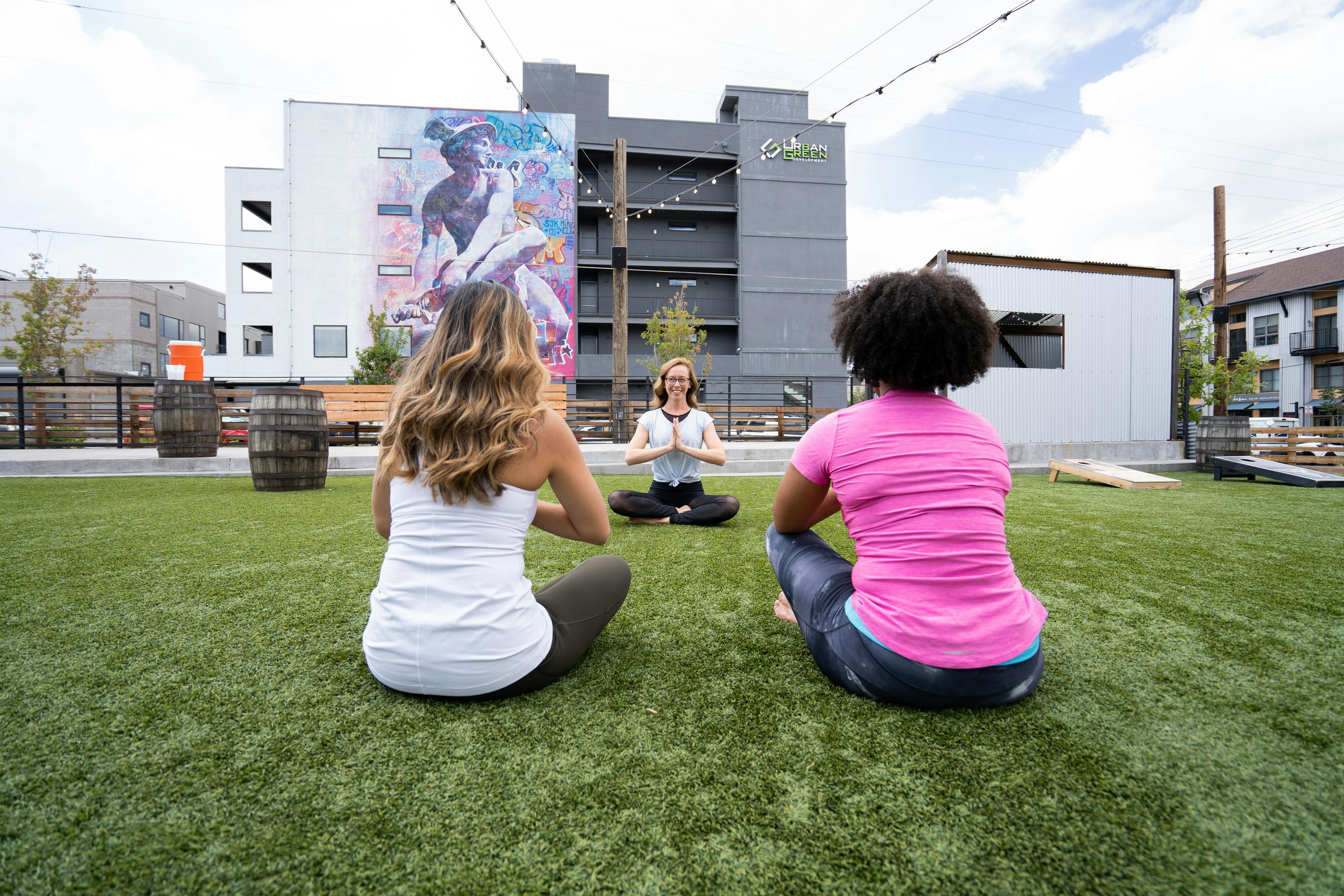 Woman In White T Shirt And Purple Pants Sitting On Green Grass Field
