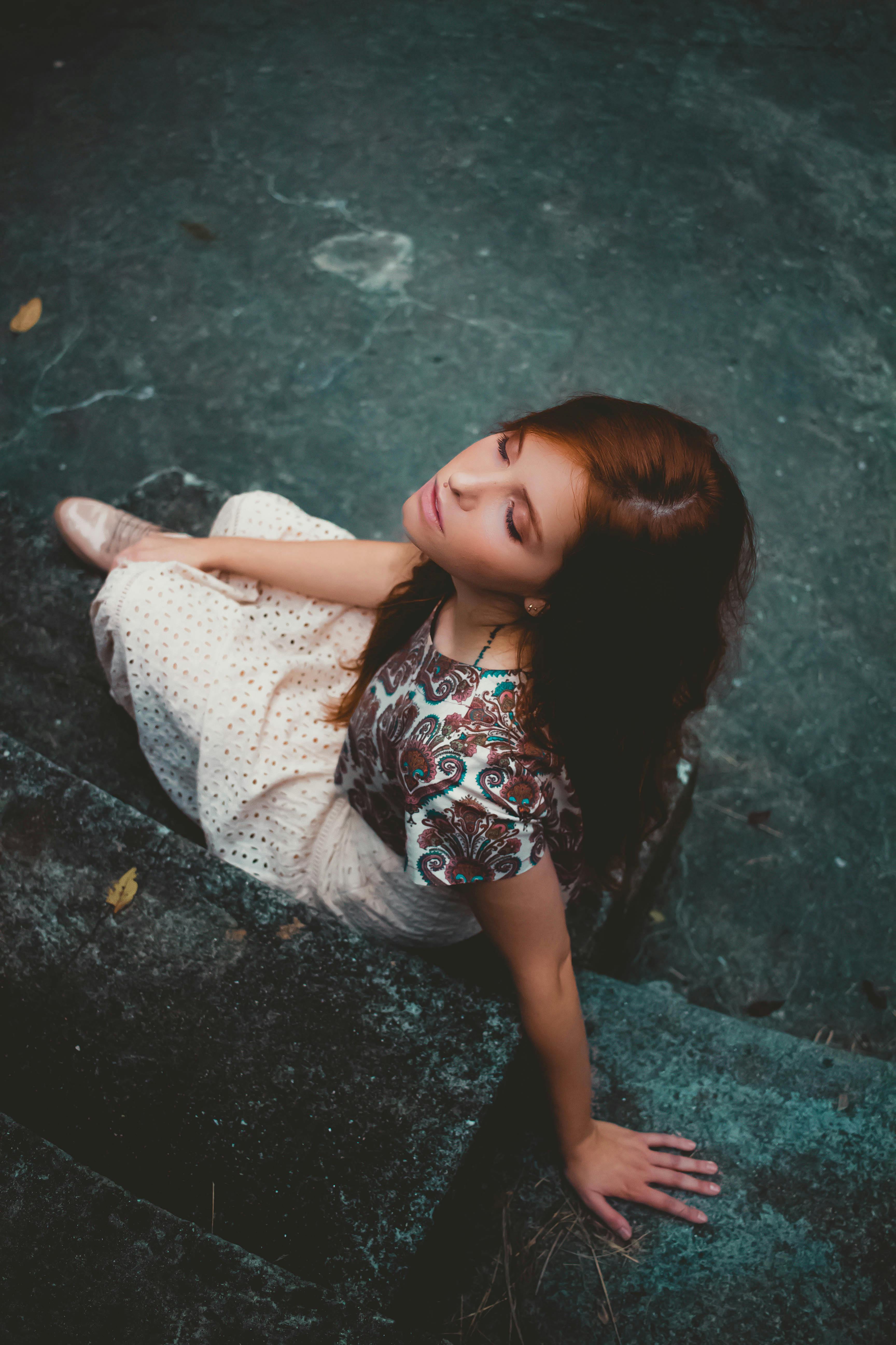 Relaxed woman sitting on asphalt ground on street · Free Stock Photo