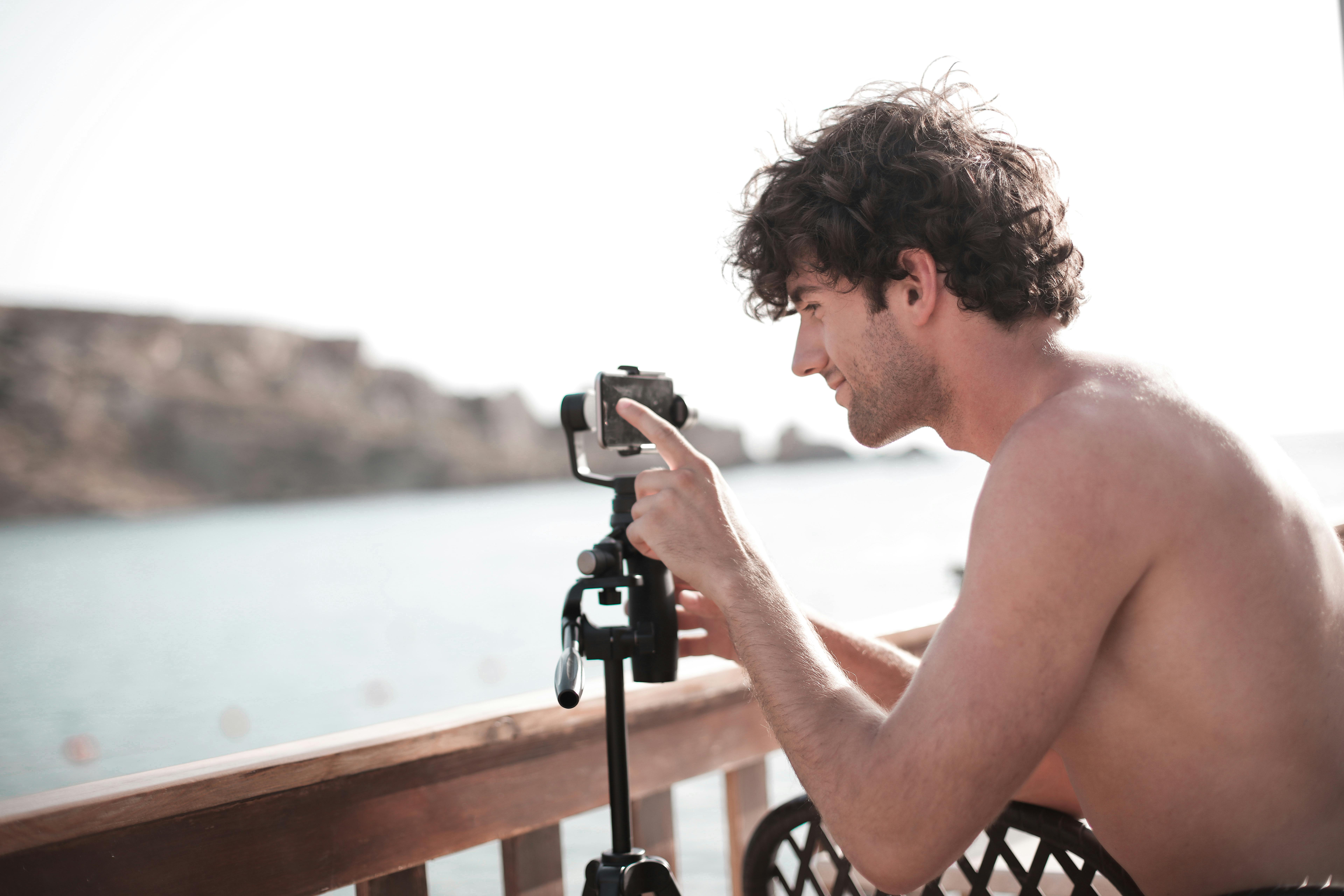 Happy man taking shot of landscape on balcony against blurred seashore ...