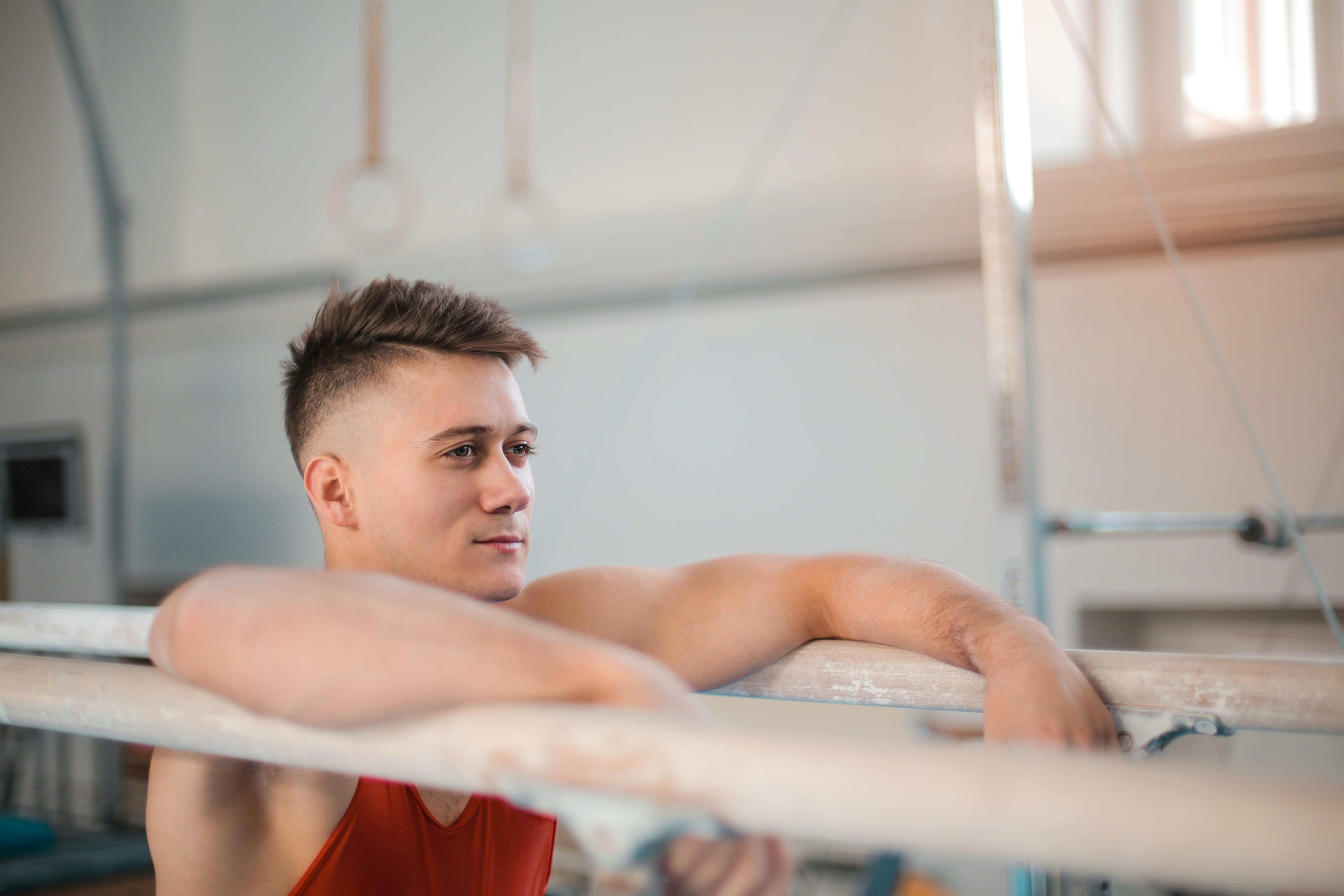 Young male gymnast standing between horizontal bars · Free Stock Photo