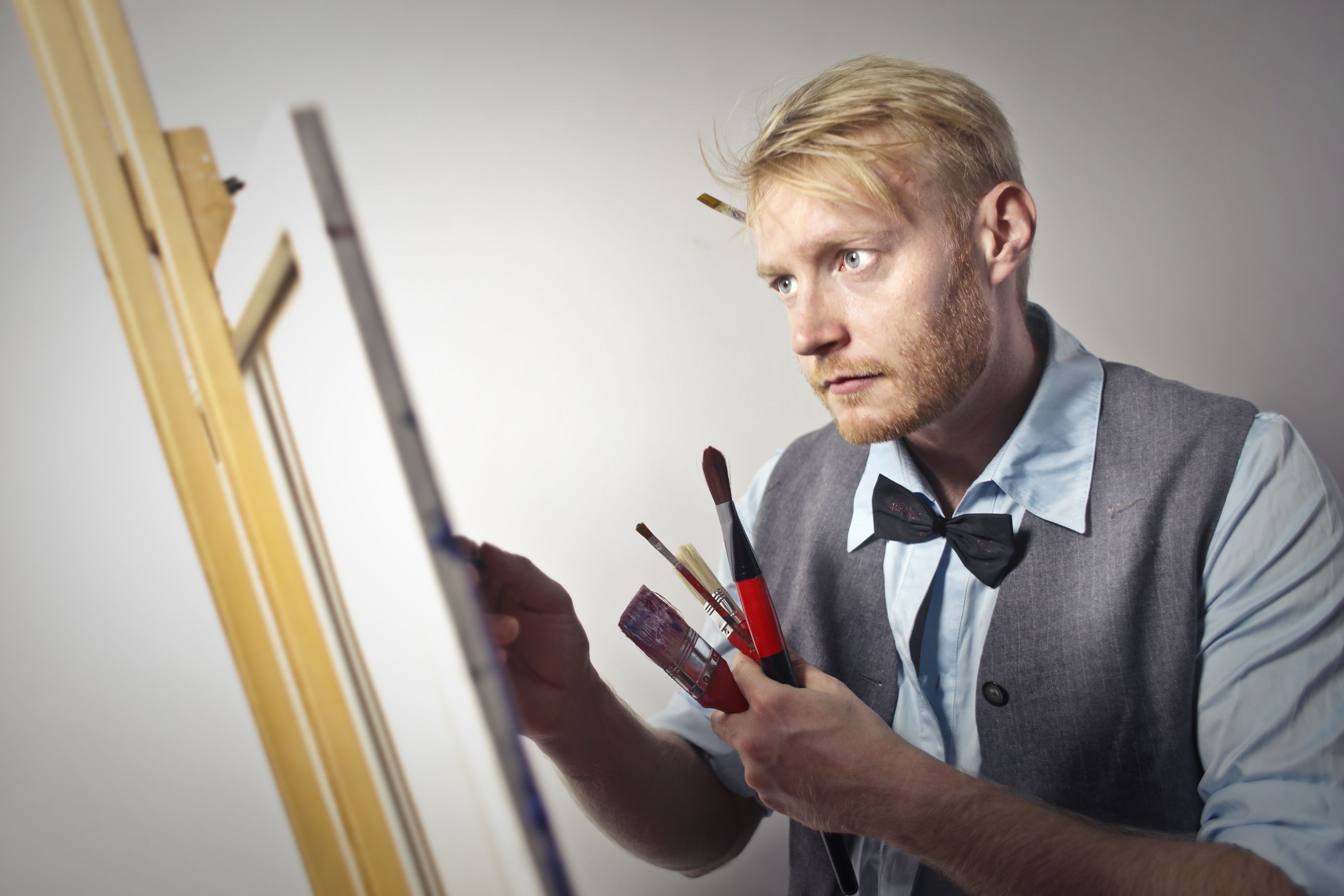 Calm male artist painting on canvas using paintbrushes · Free Stock Photo
