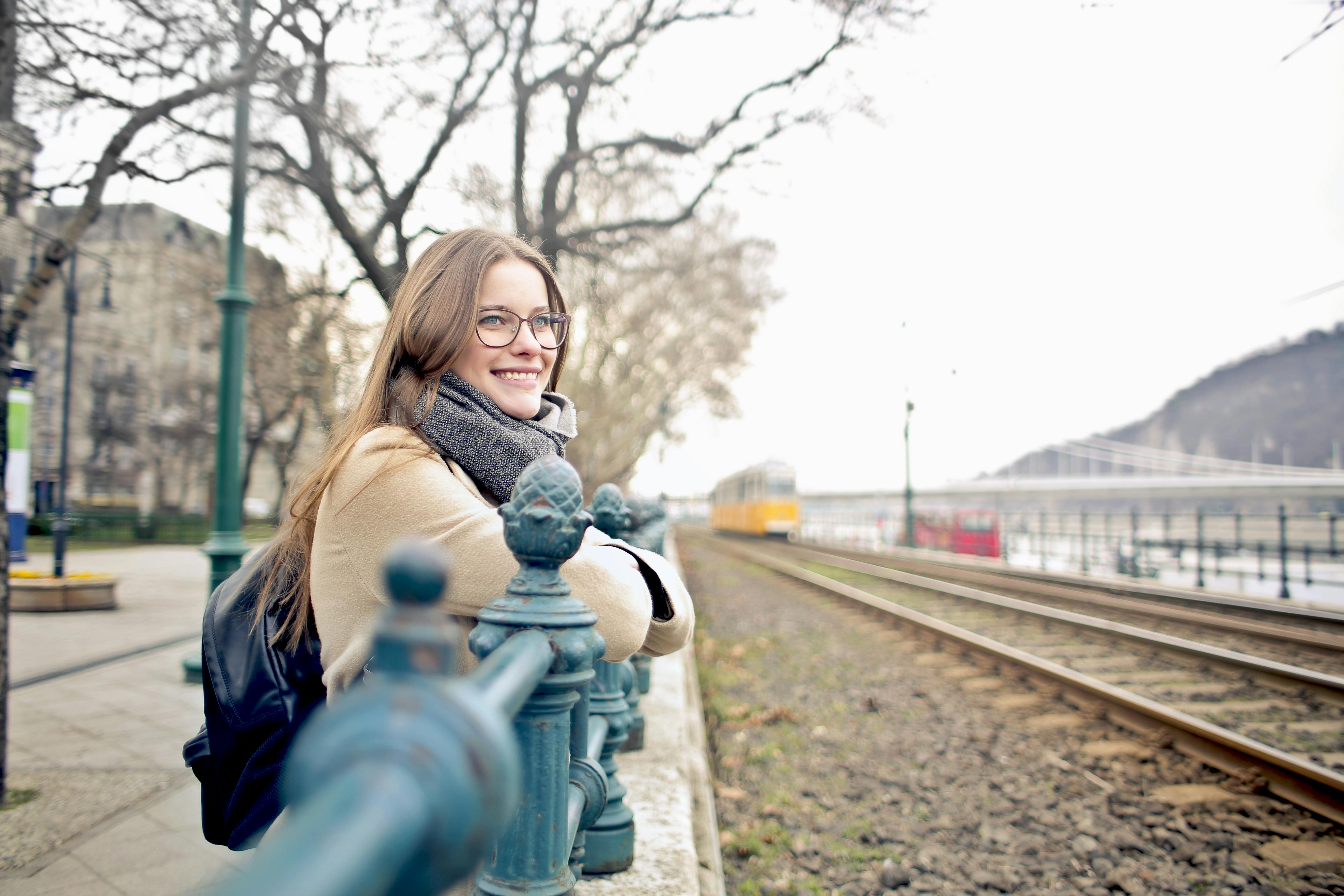 Woman in Brown Jacket Leaning Over Blue Handrail · Free Stock Photo