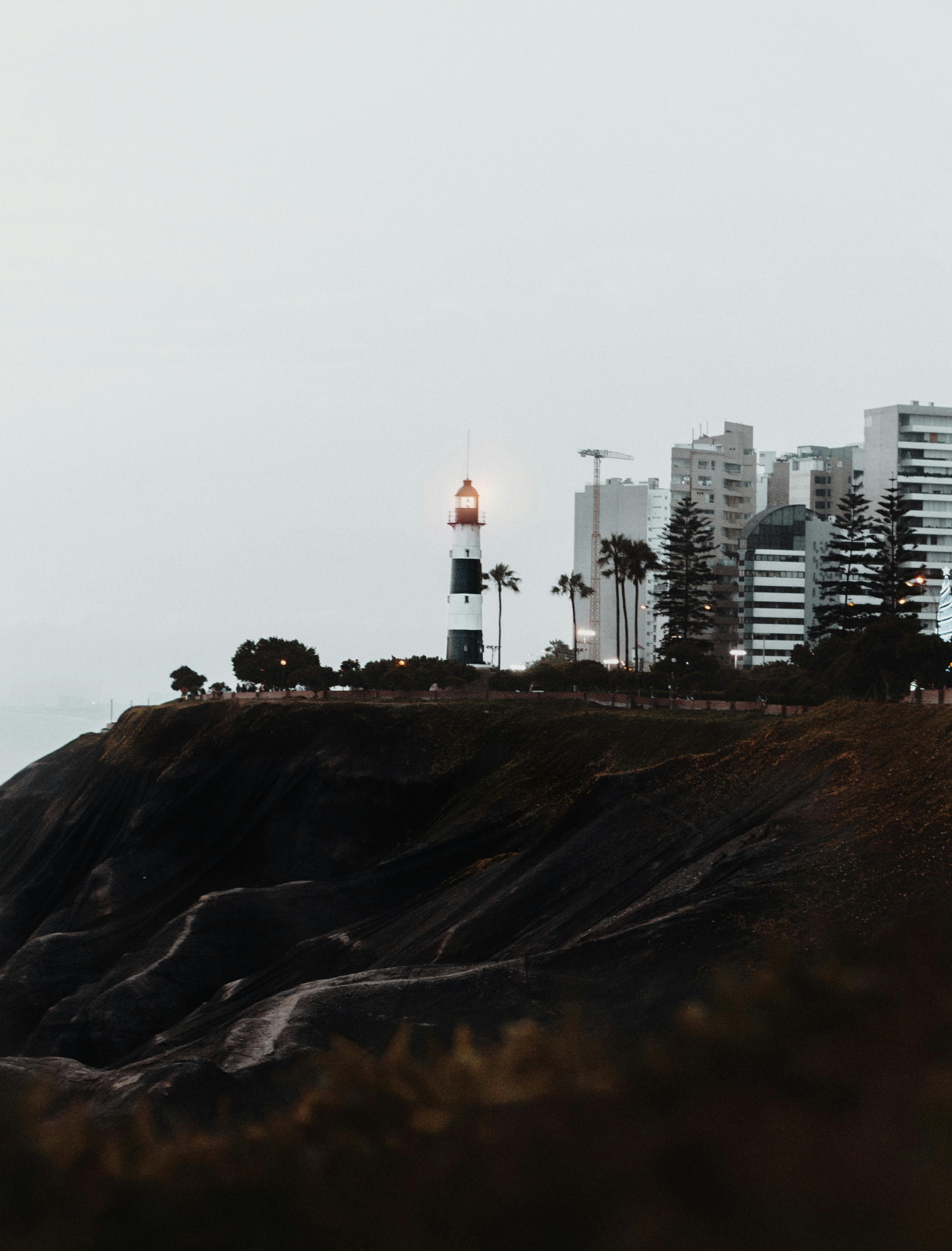 White and Black Lighthouse Near Cliff · Free Stock Photo