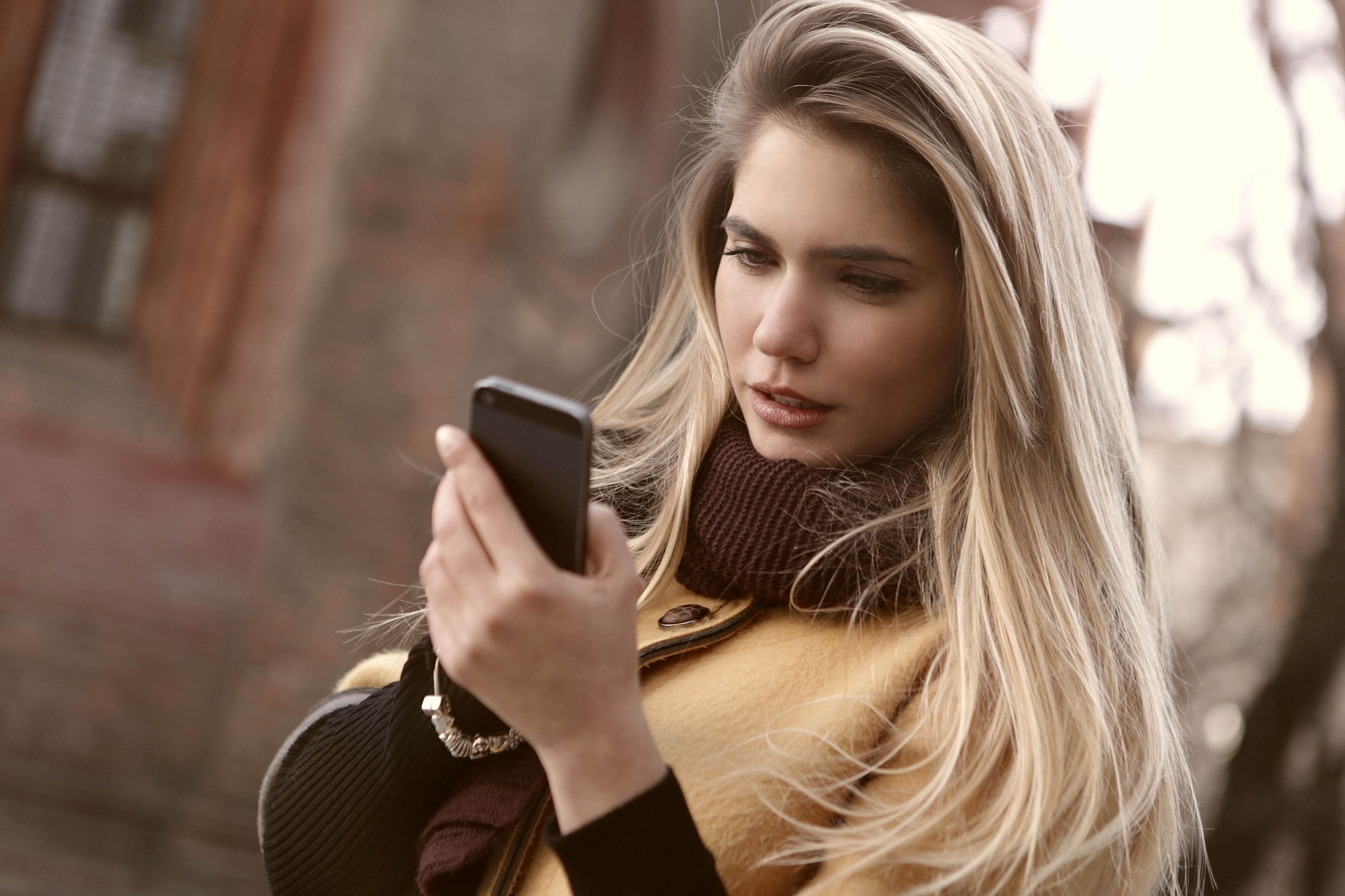 Woman in Black Knit Sweater Holding Black Smartphone · Free Stock Photo