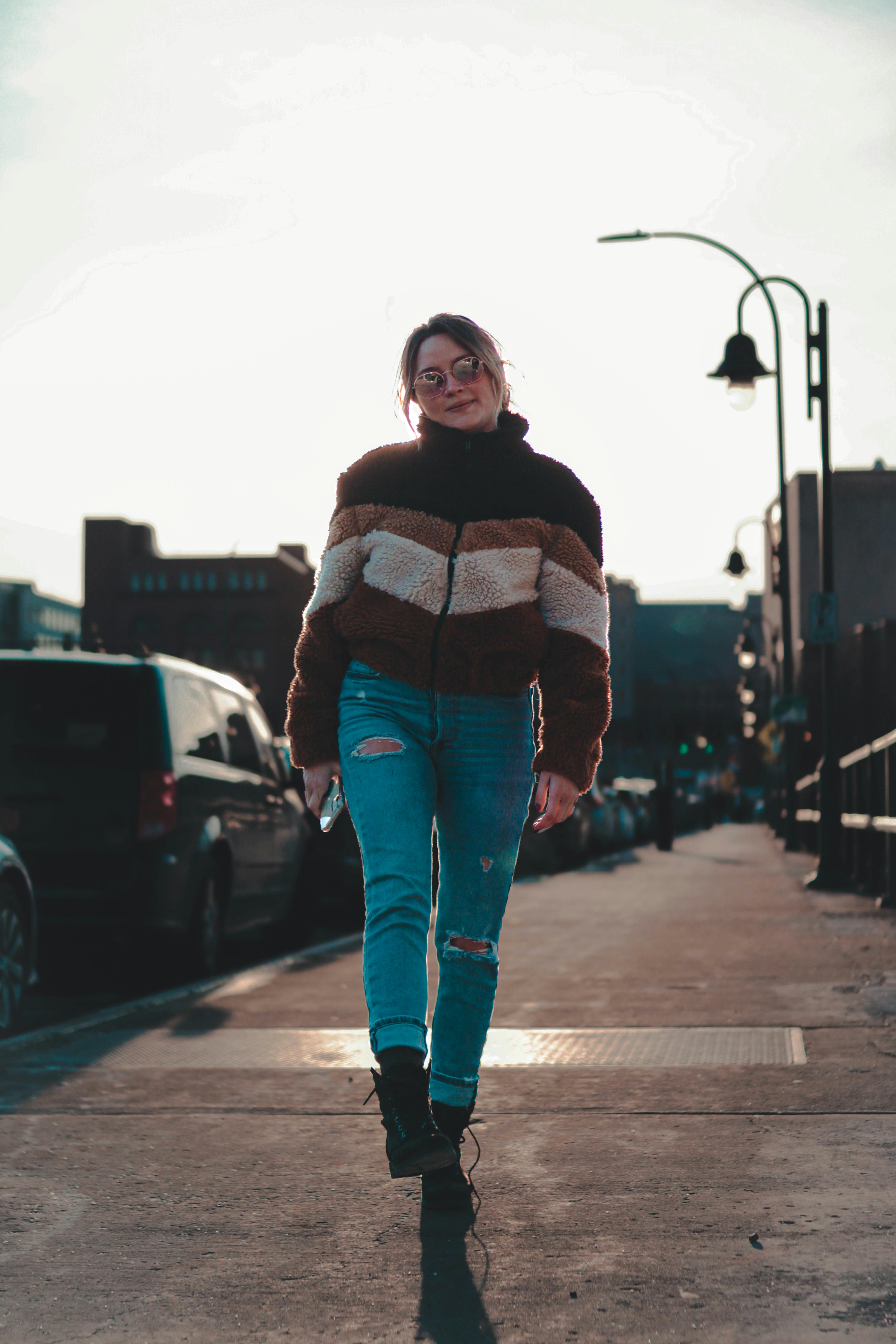 Woman in Blue Denim Jeans Walking on Sidewalk · Free Stock Photo