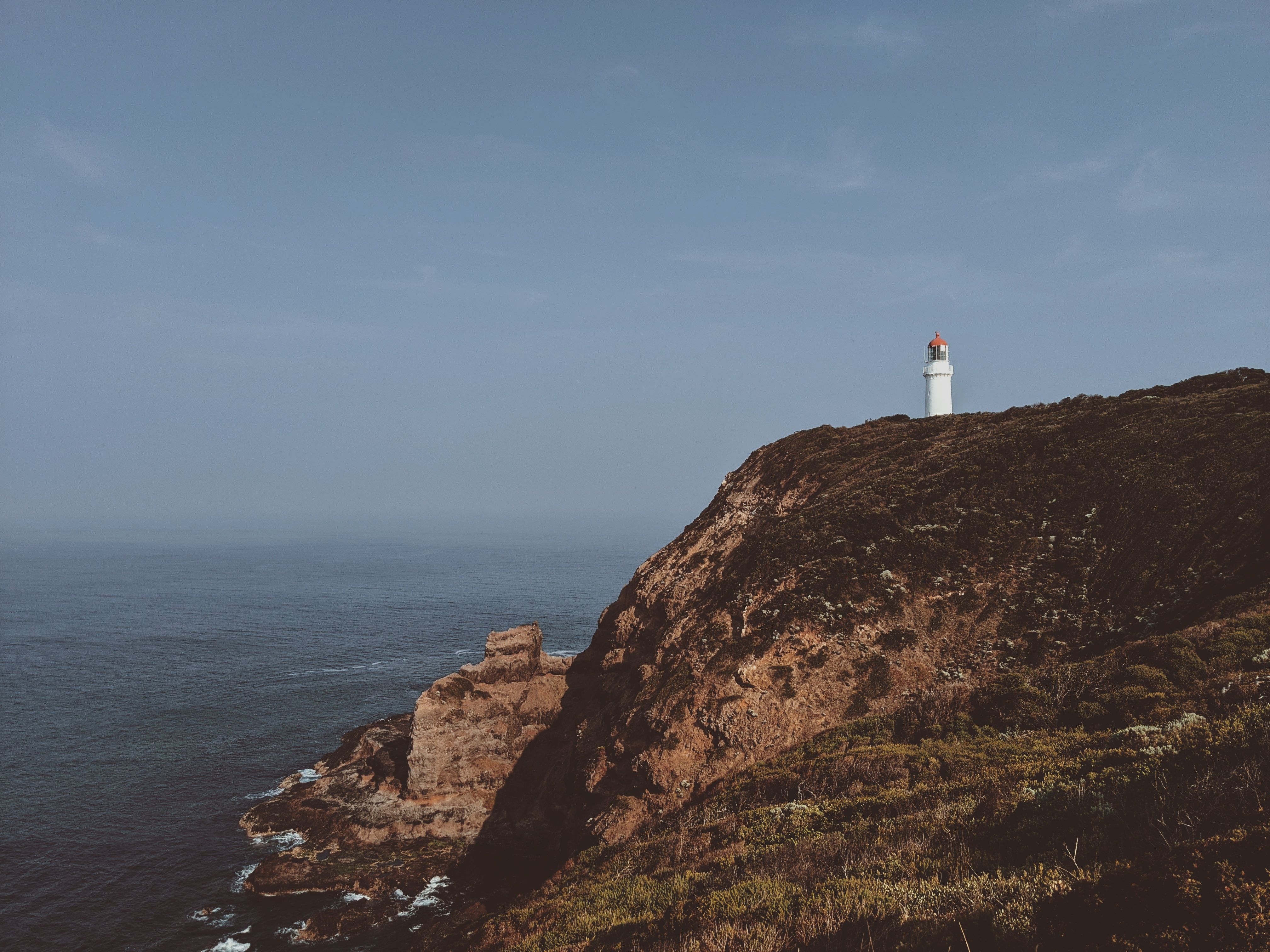 Photo of Lighthouse on Cliff Near Body of Water · Free Stock Photo