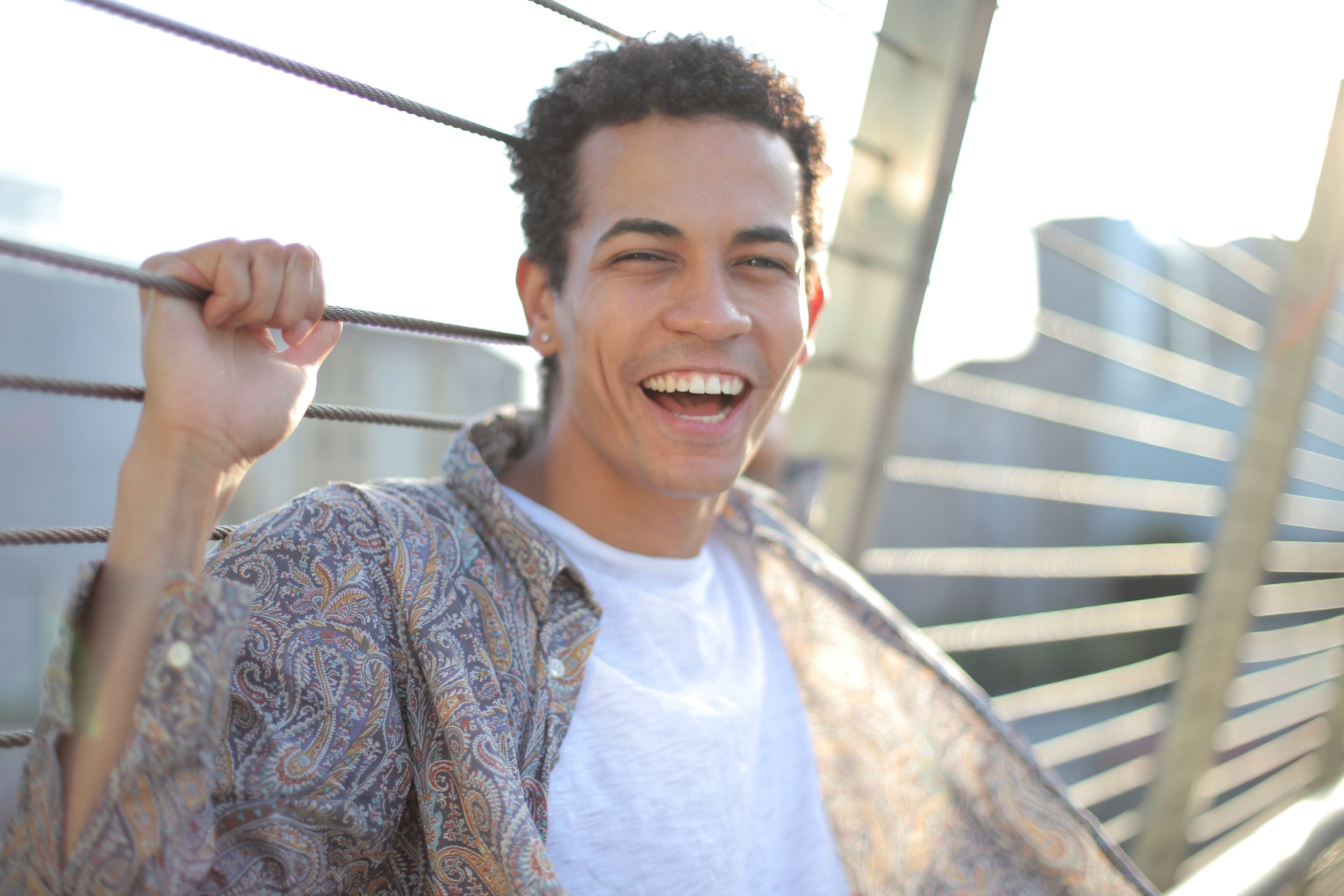Cheerful casual man laughing near fence · Free Stock Photo