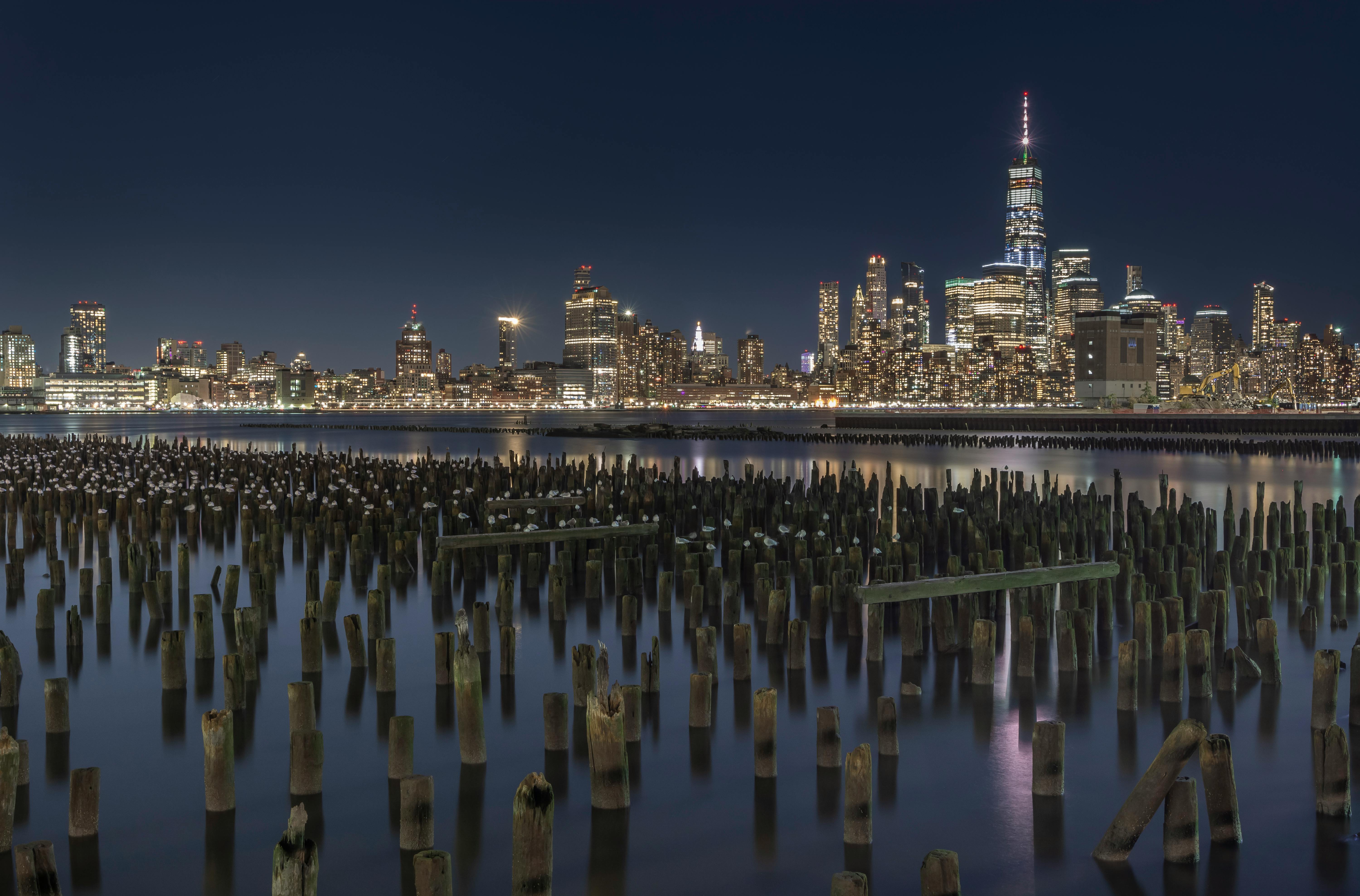 Modern city skyline on riverbank at night · Free Stock Photo