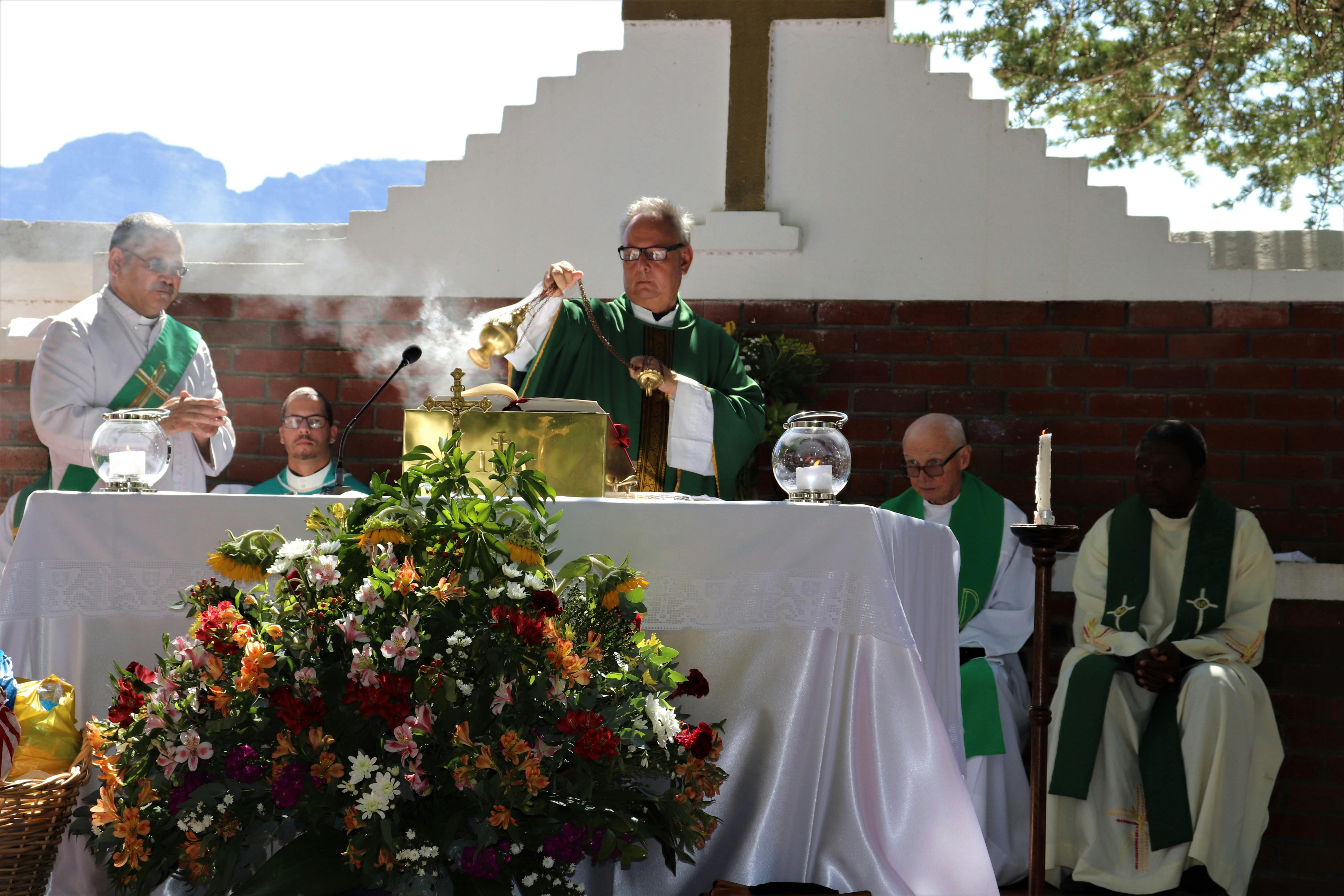 Senior priest waving incense during church service near multiracial ...