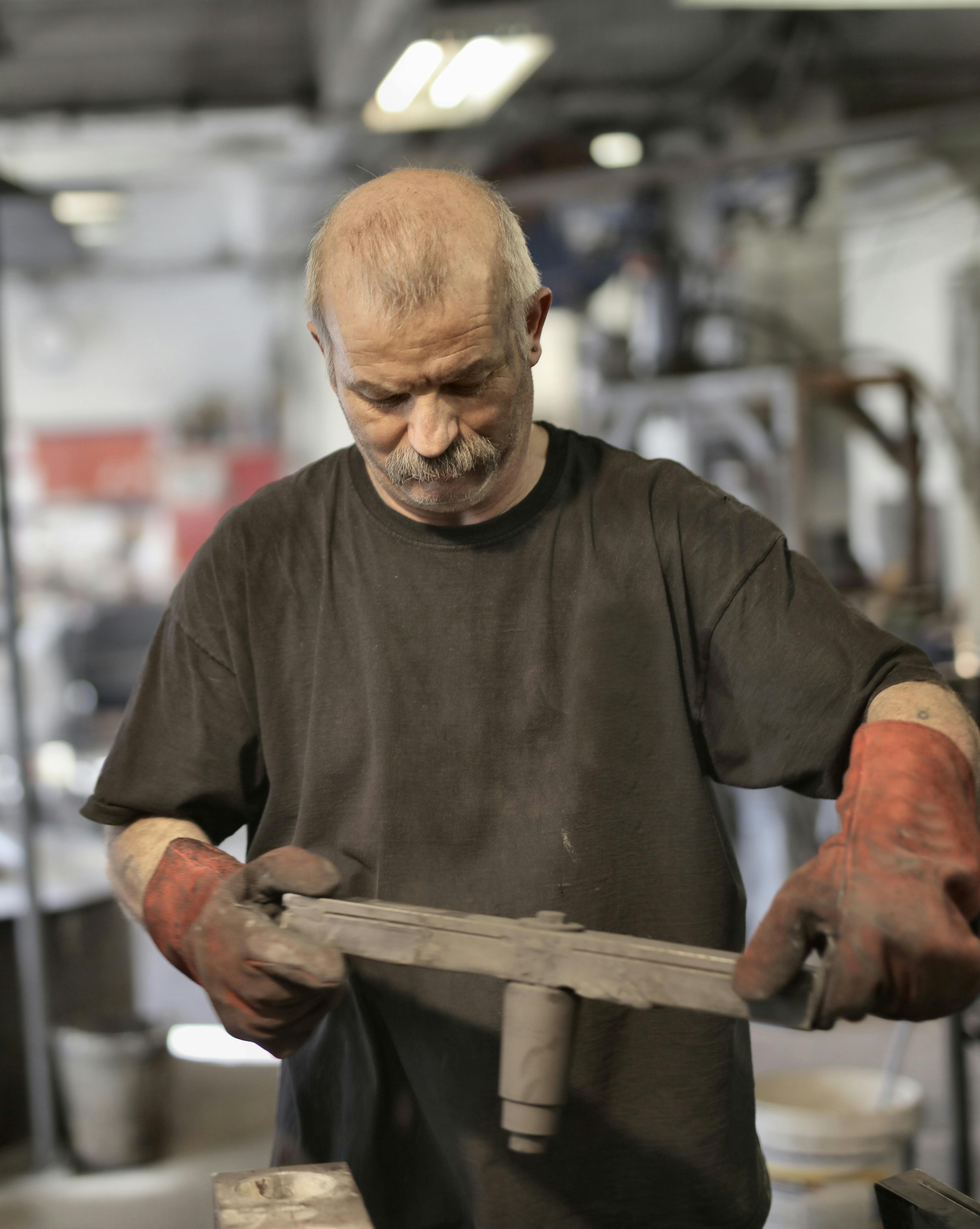 Focused senior fitter assembling detail in workshop · Free Stock Photo