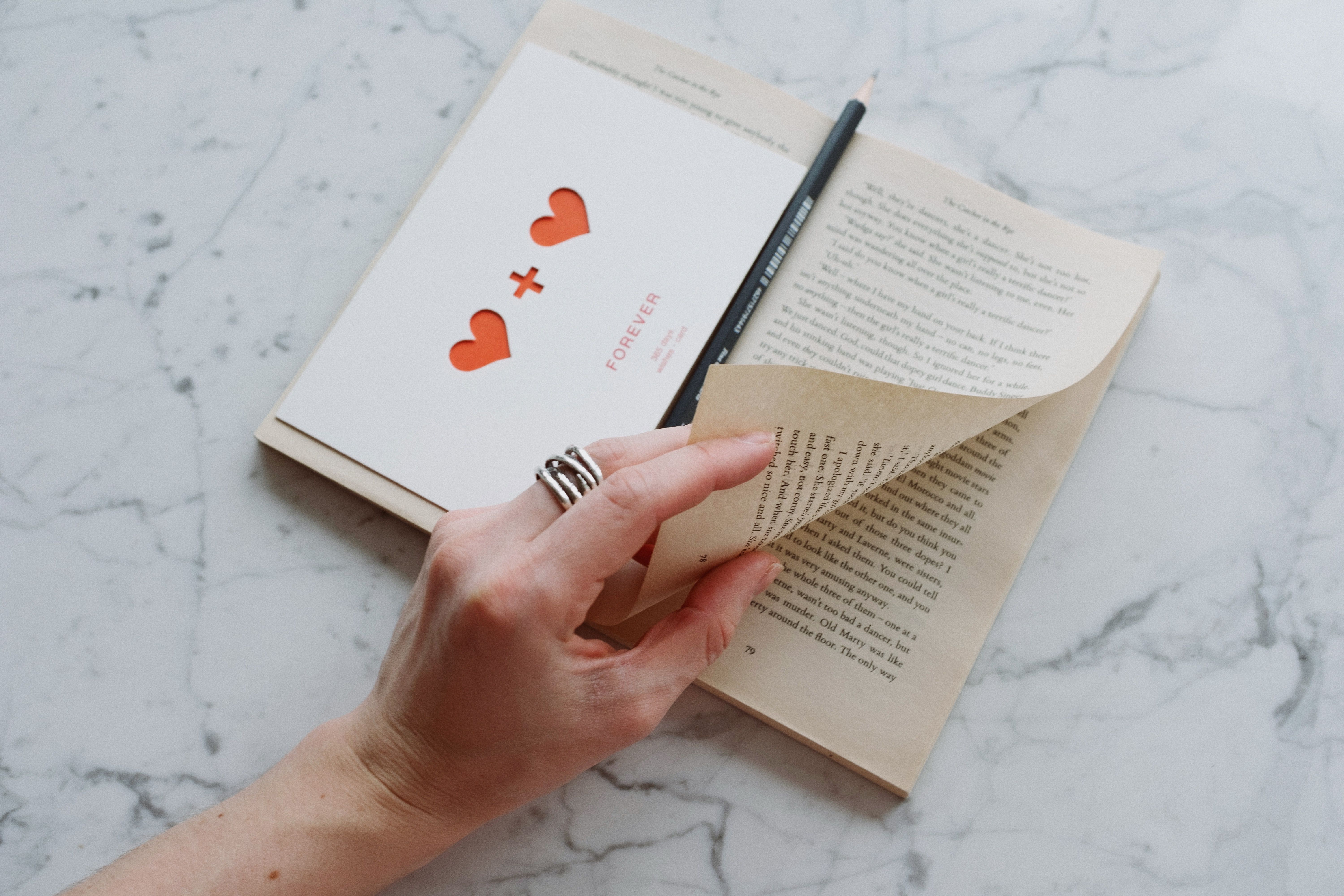 Anonymous crop person reading book on marble surface · Free Stock Photo