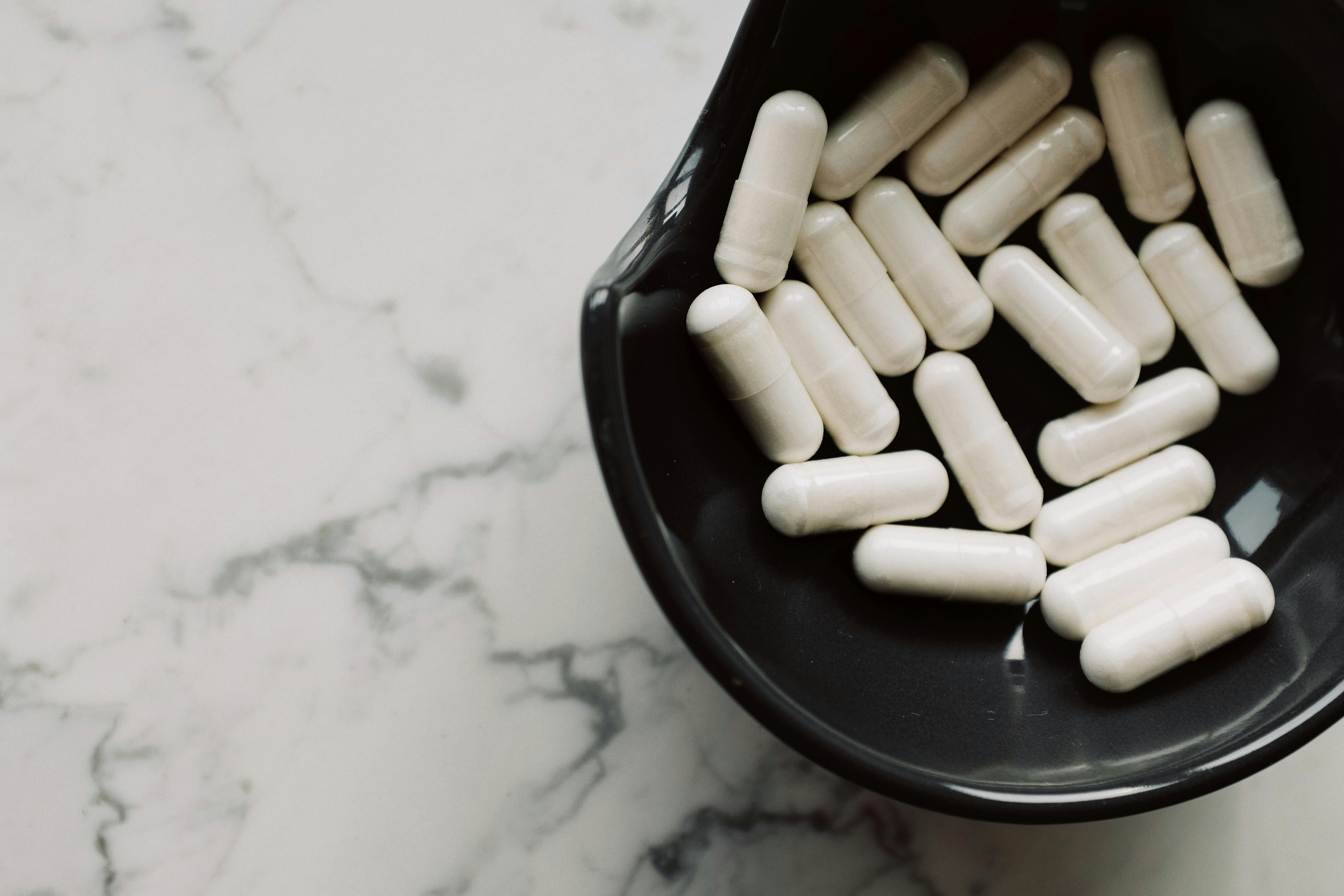 White Medication Pill on Black Ceramic Bowl · Free Stock Photo