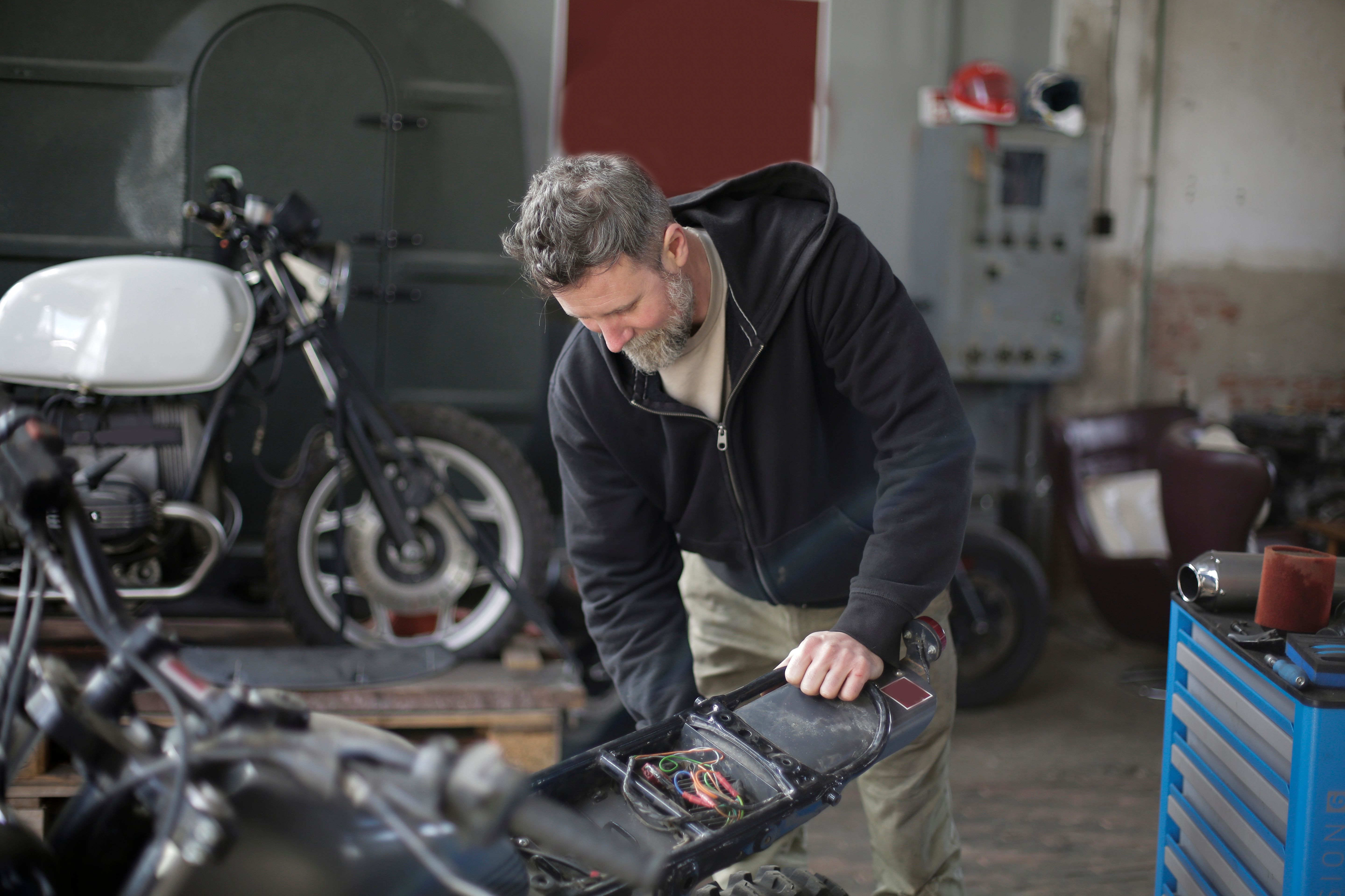 Serious adult male mechanic repairing motorbike in garage · Free Stock ...