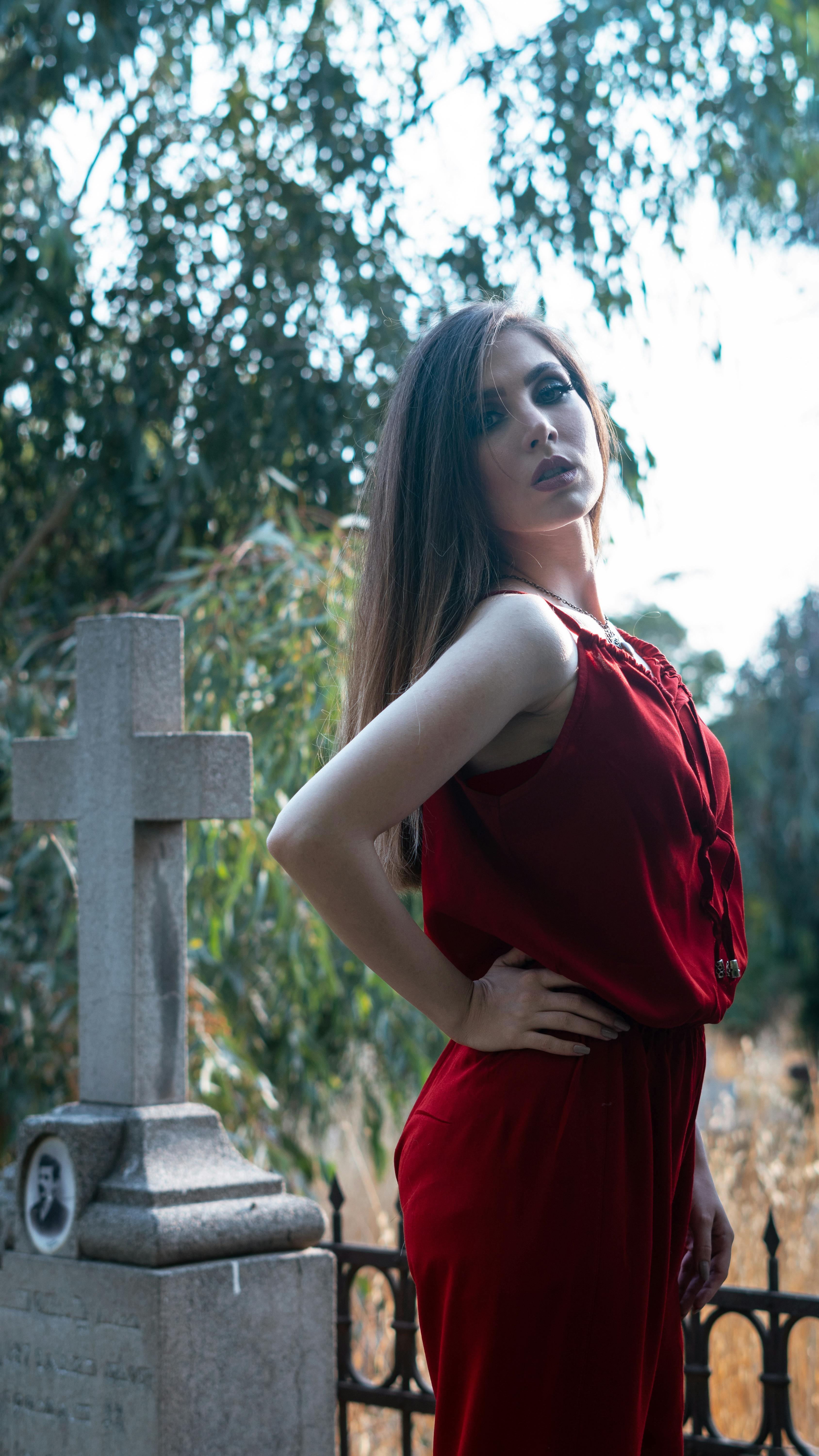 Elegant woman standing near stone cross · Free Stock Photo