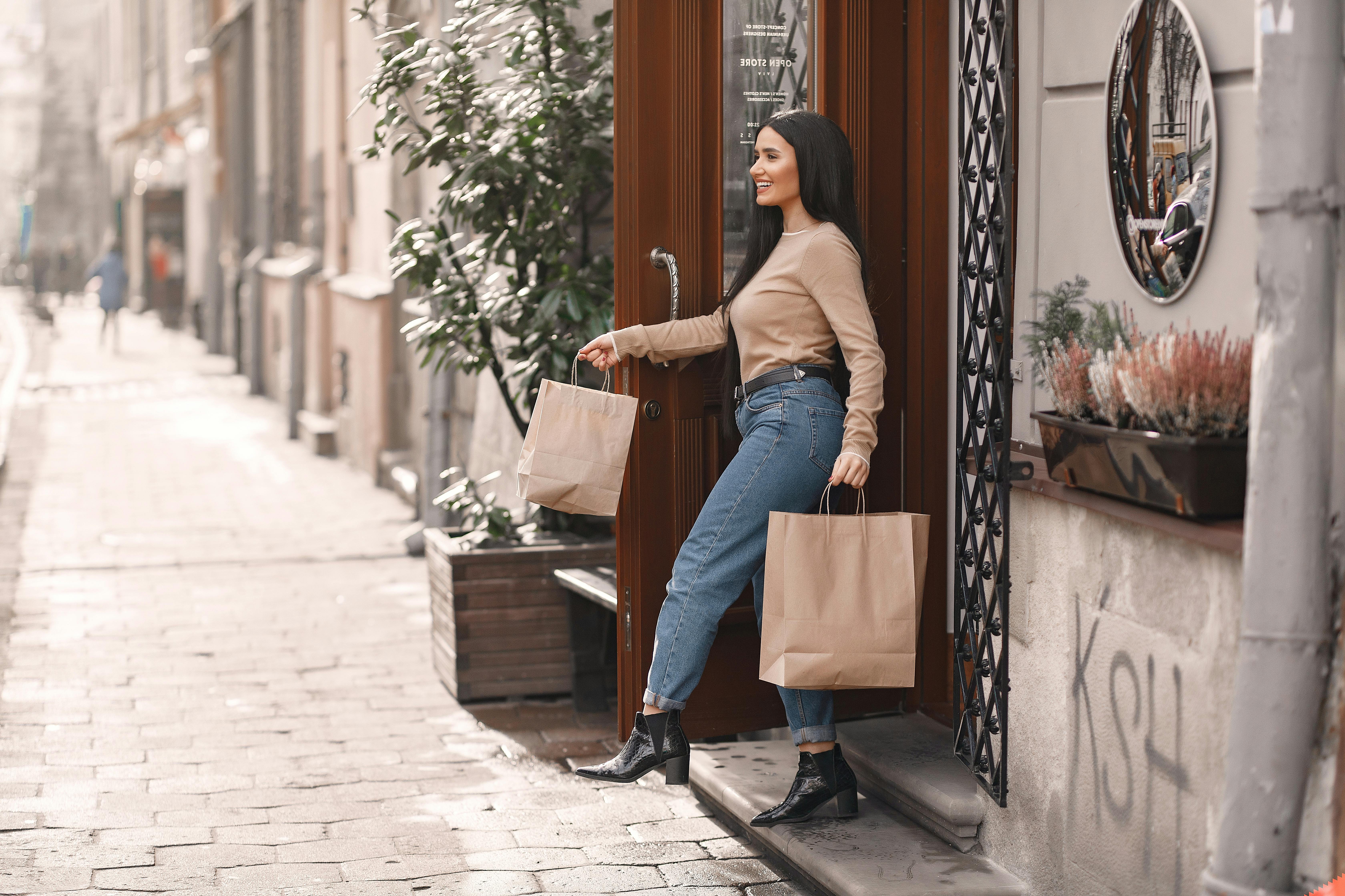Happy woman coming out of store with paper bags · Free Stock Photo