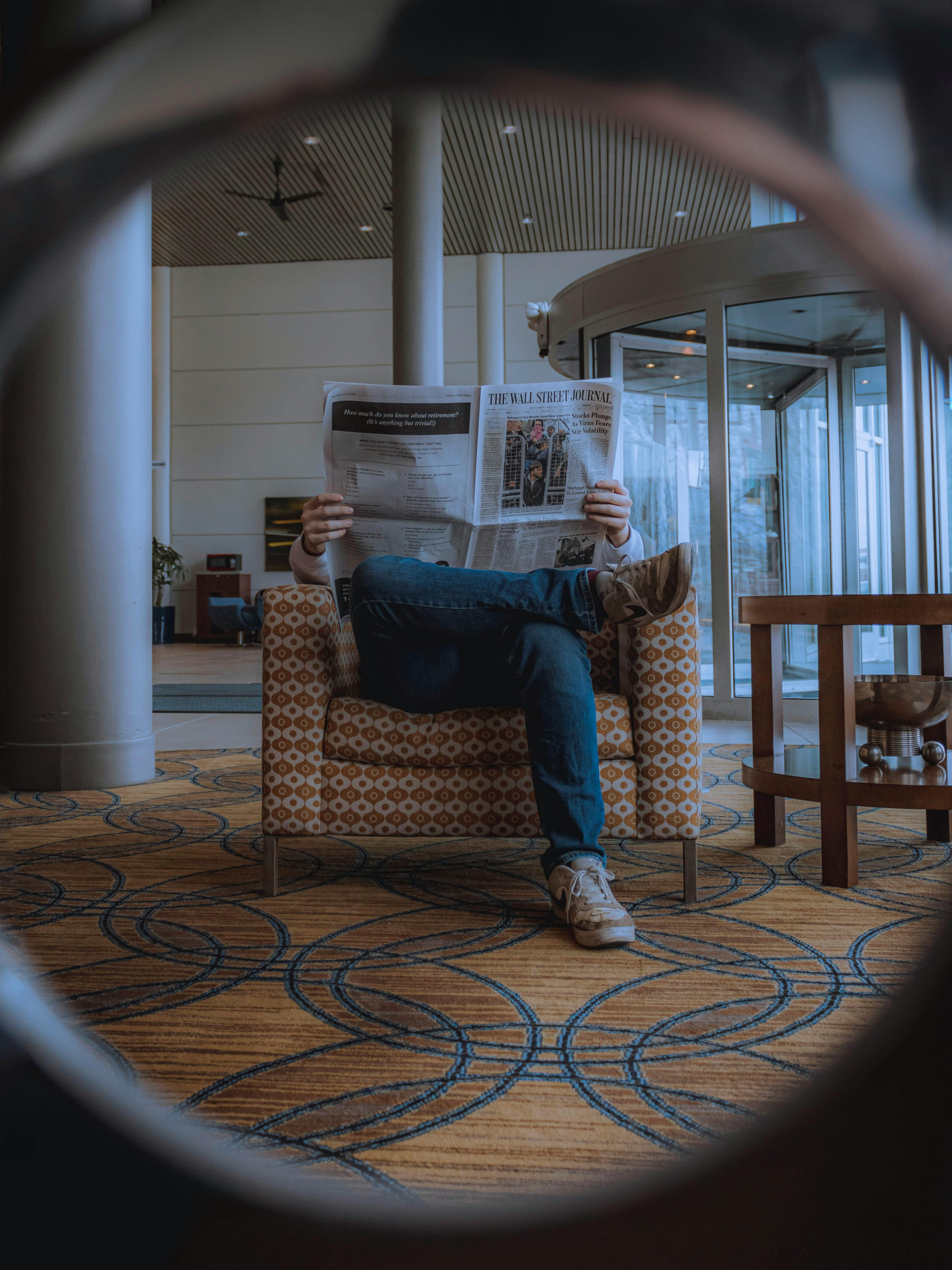 Man Sitting On Brown Sofa Chair Reading The Newspaper · Free Stock Photo
