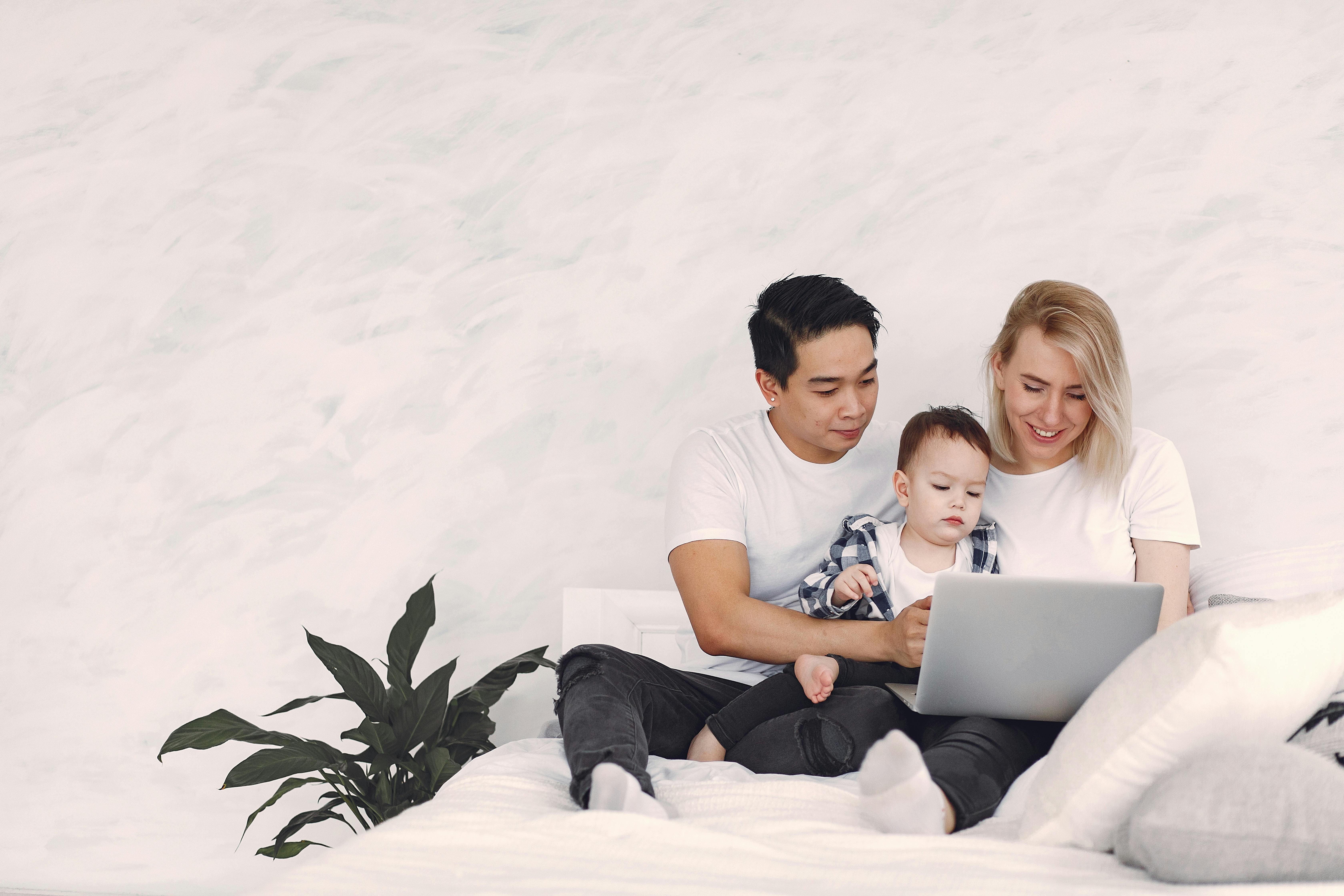 Man And Woman Holding Their Child While Looking At Laptop Screen · Free ...