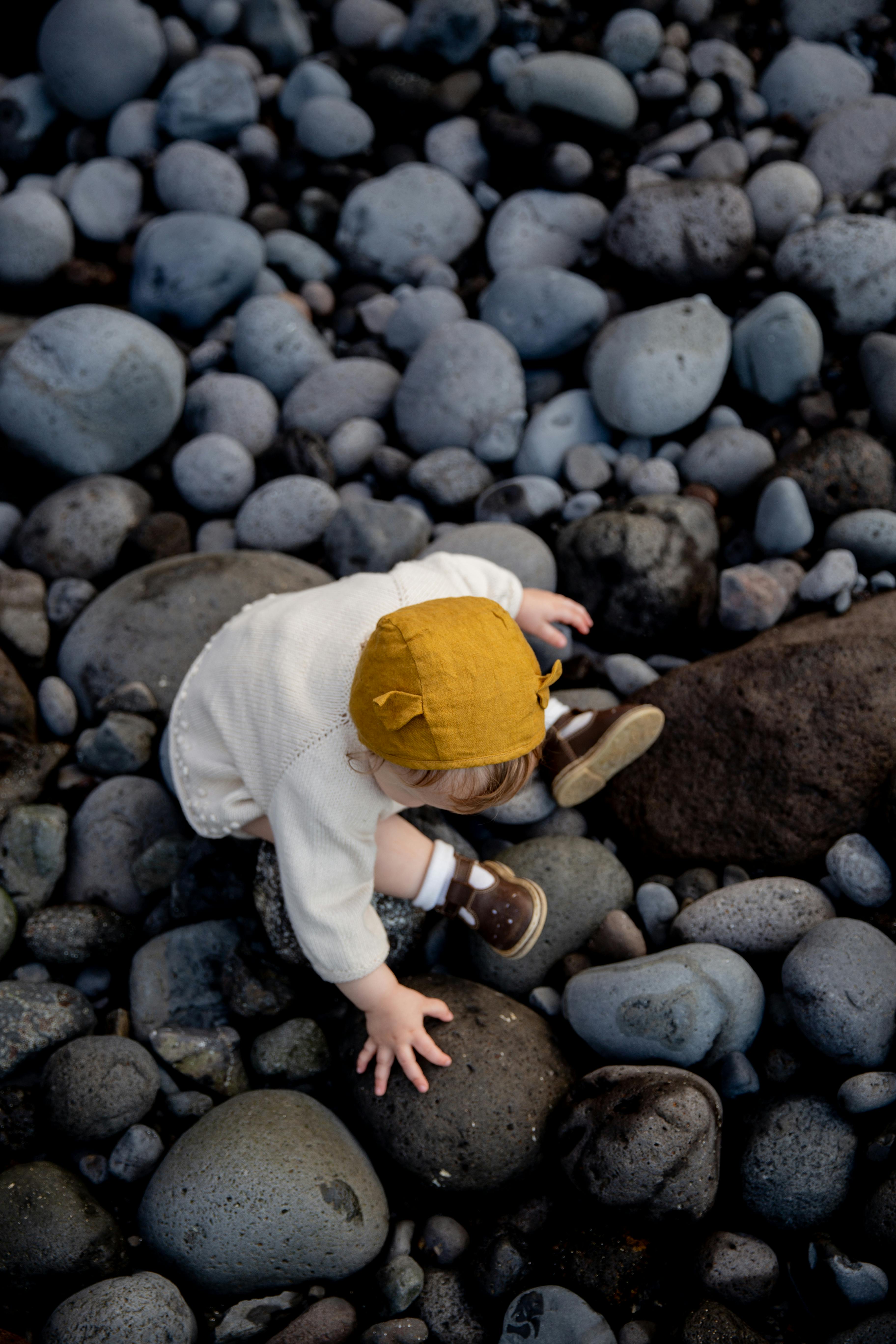 A Baby Sitting On Rocks · Free Stock Photo
