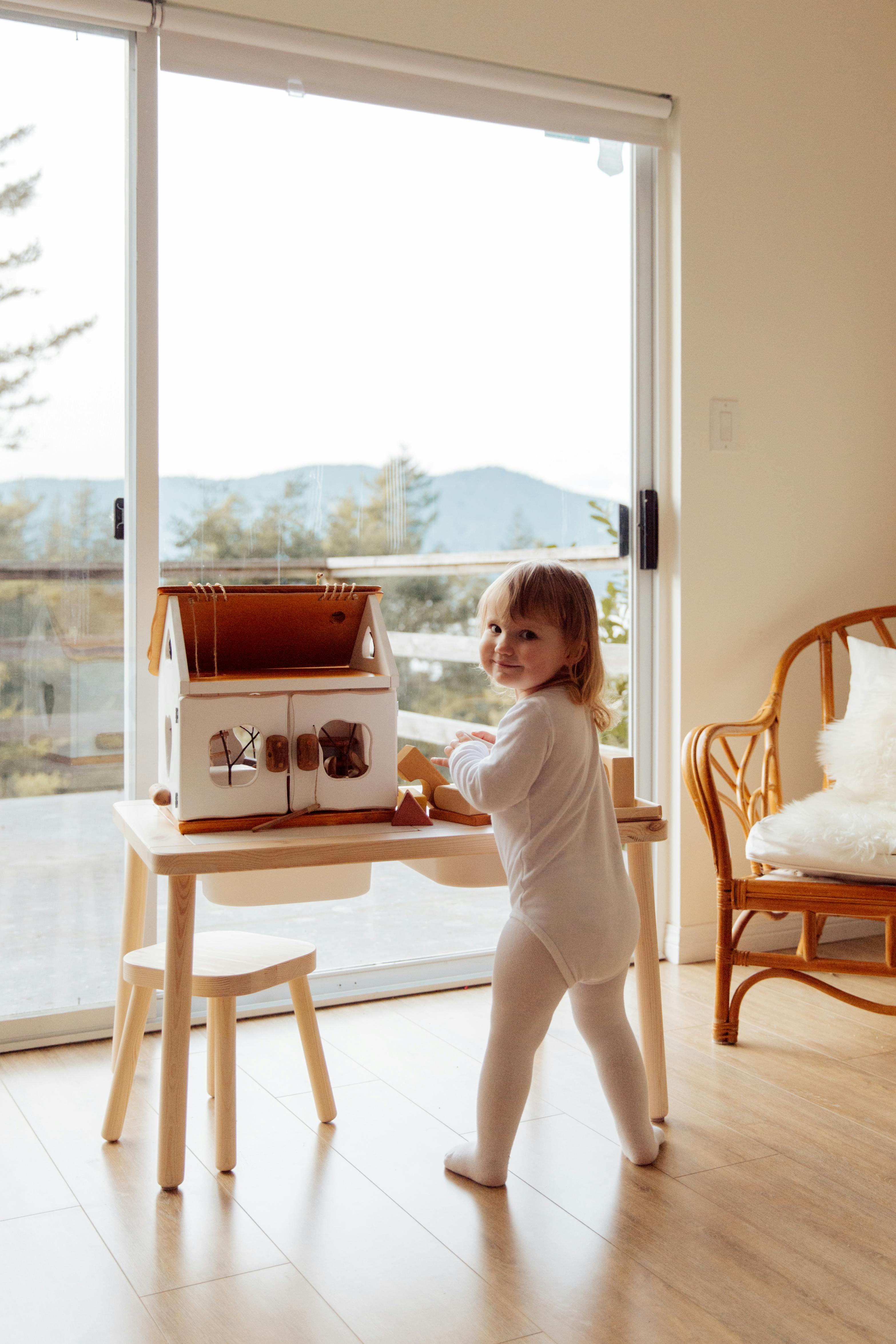 Photo Of Child Standing Near Wooden Chair · Free Stock Photo