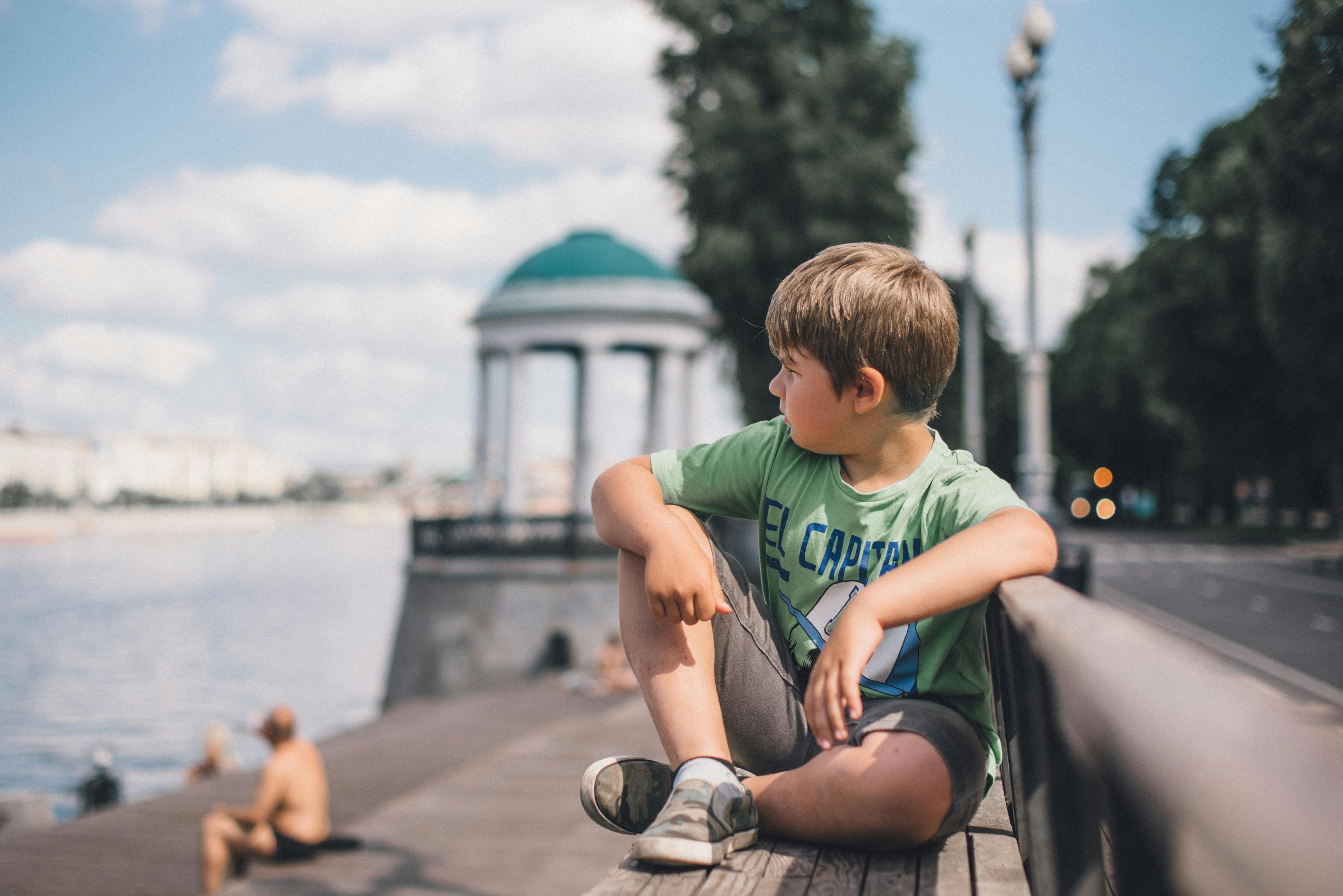 Photo of Boy Sitting On Bench · Free Stock Photo