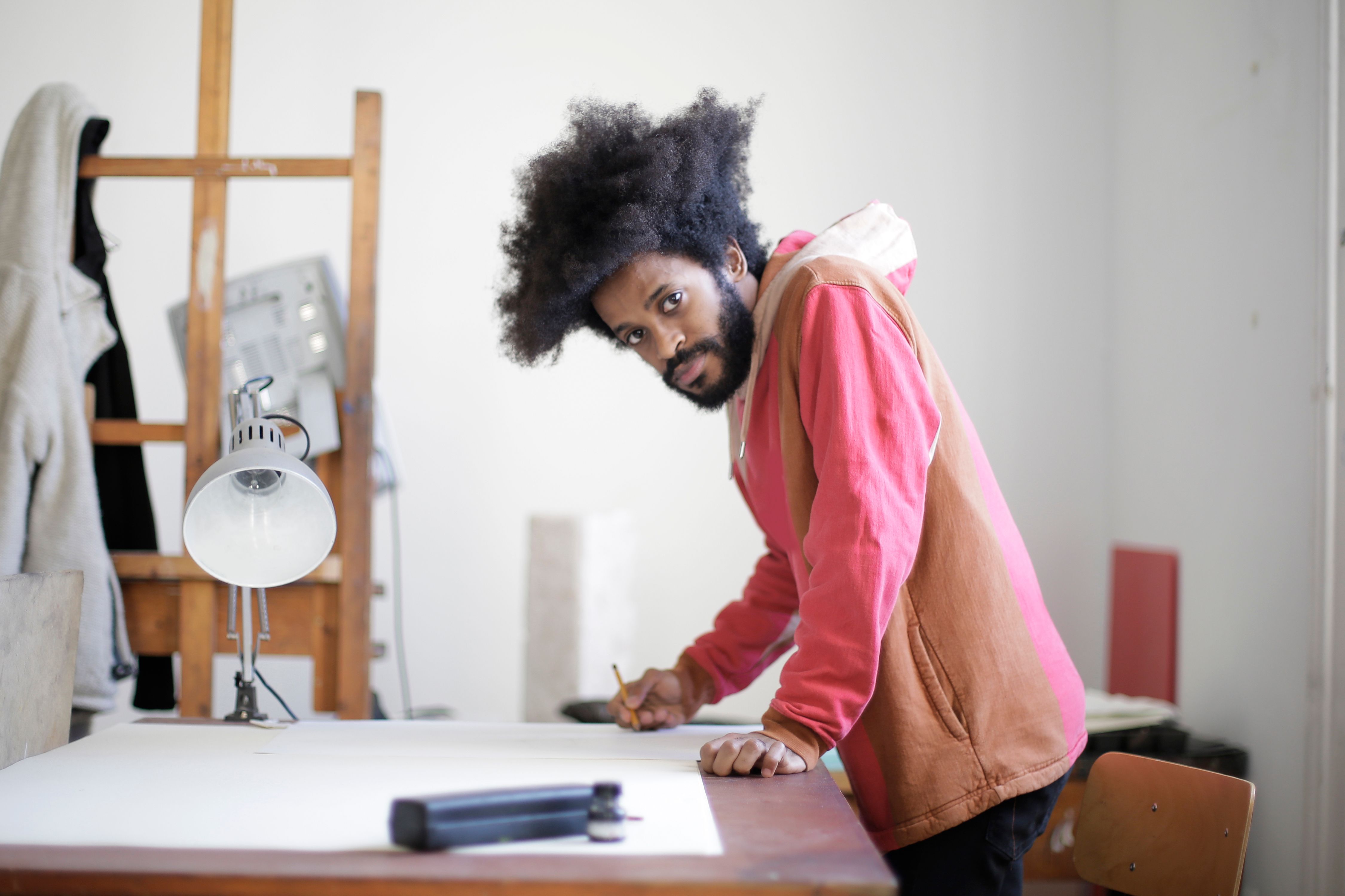 Young creative male painter drawing sketch in aged studio interior ...