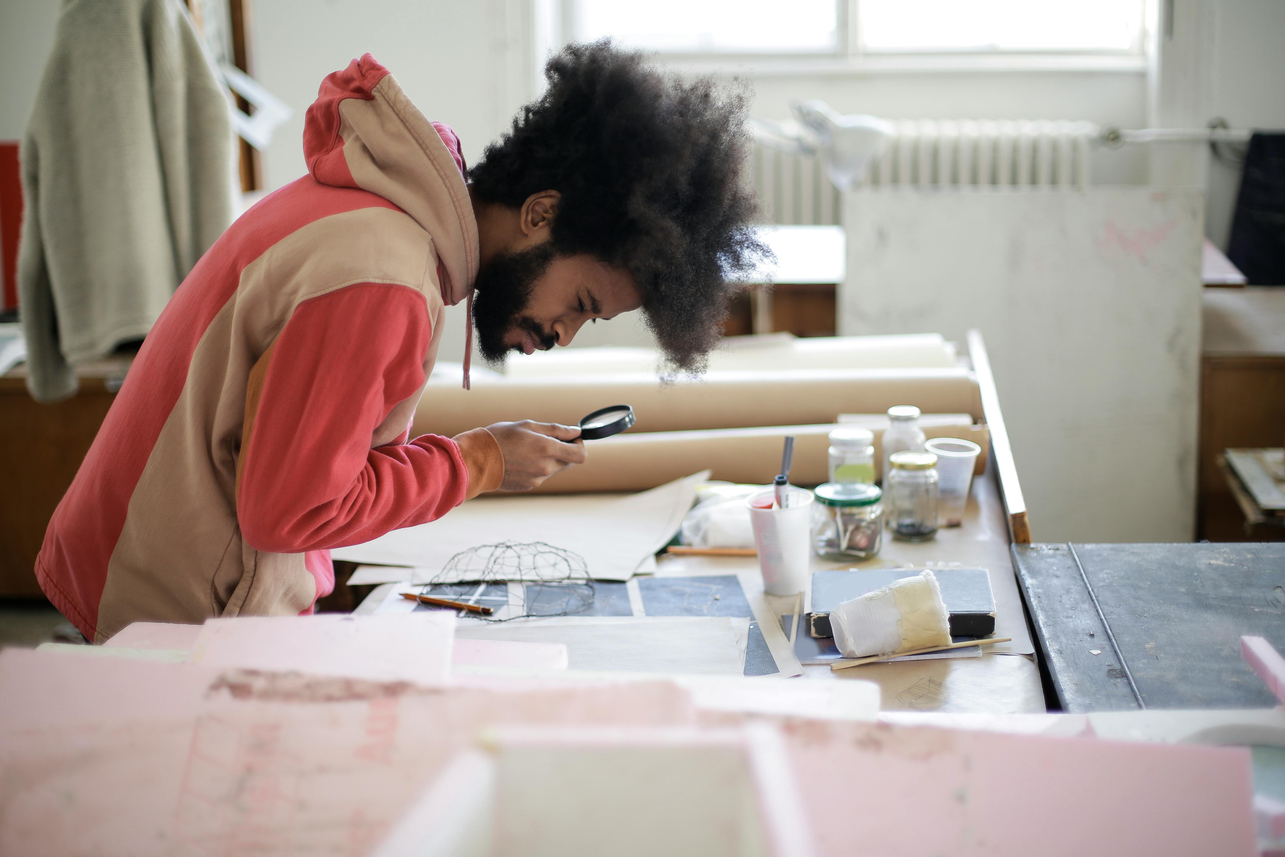 Man Leaning Over Table Using Magnifying Lens · Free Stock Photo