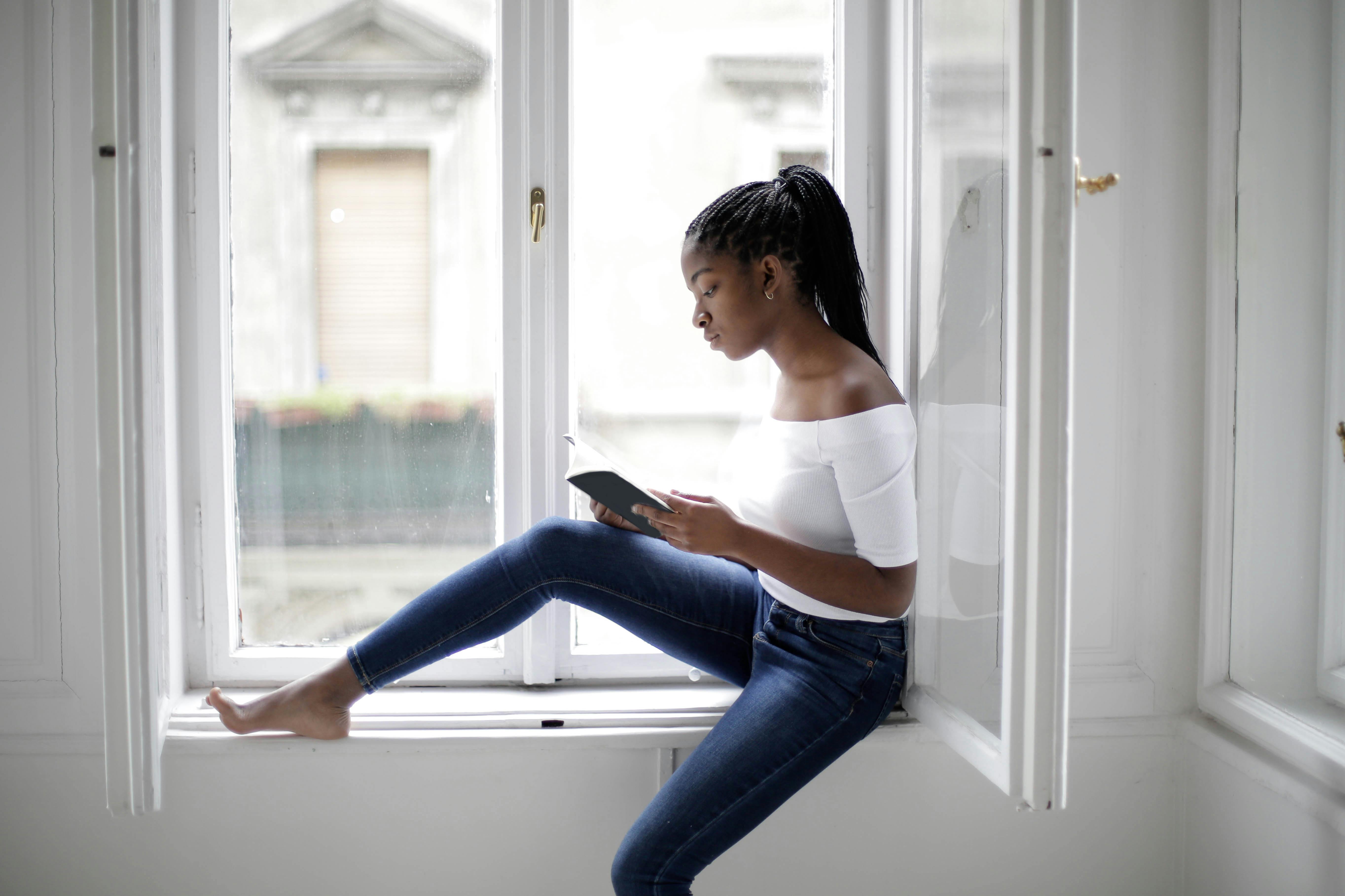 Woman in White Tank Top and Blue Denim Jeans Sitting on Windowsill ...