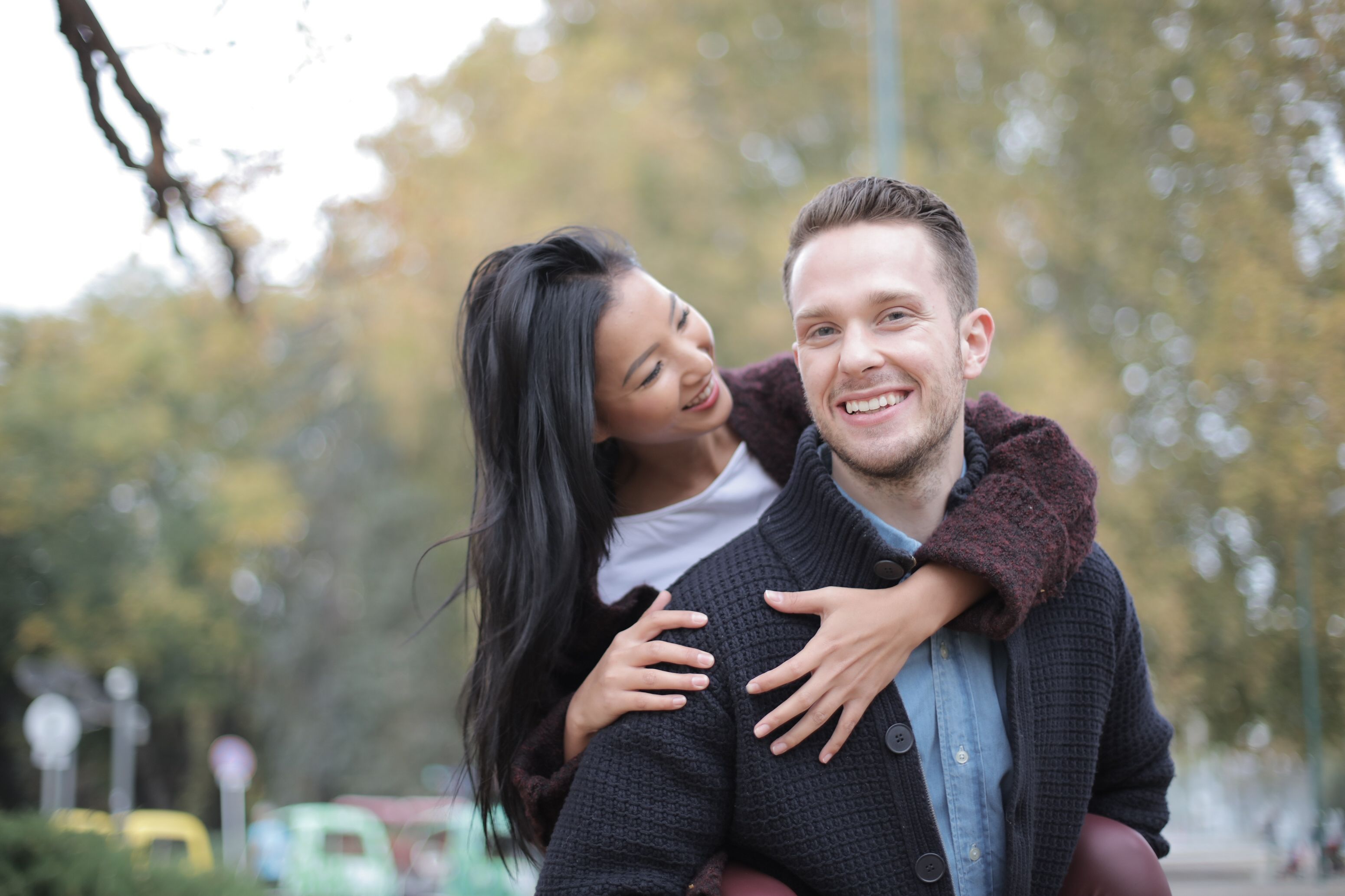 Cheerful young multiethnic couple hugging while walking together in ...