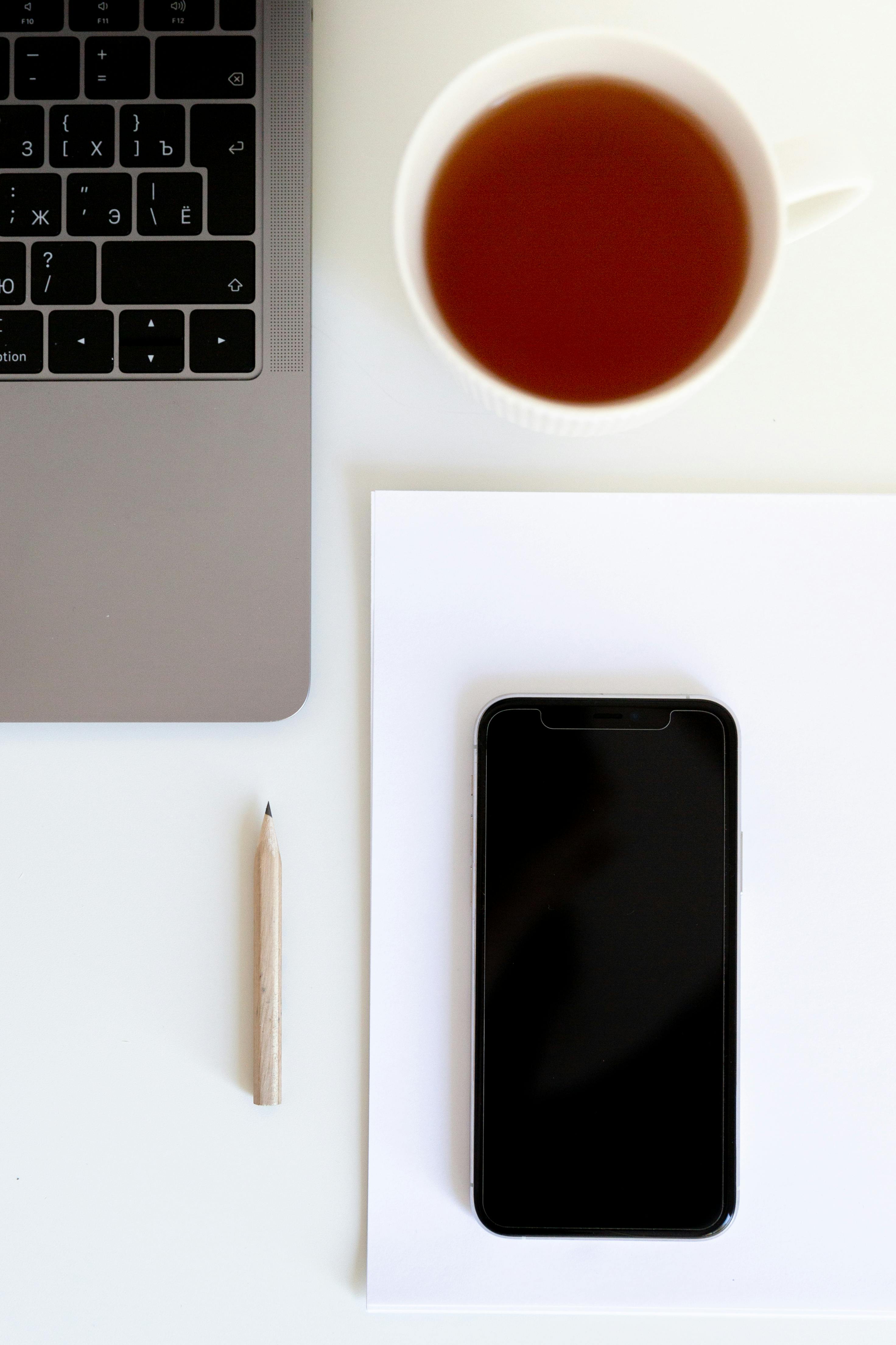 Cup of tea near laptop keyboard with smartphone on paper and wooden ...